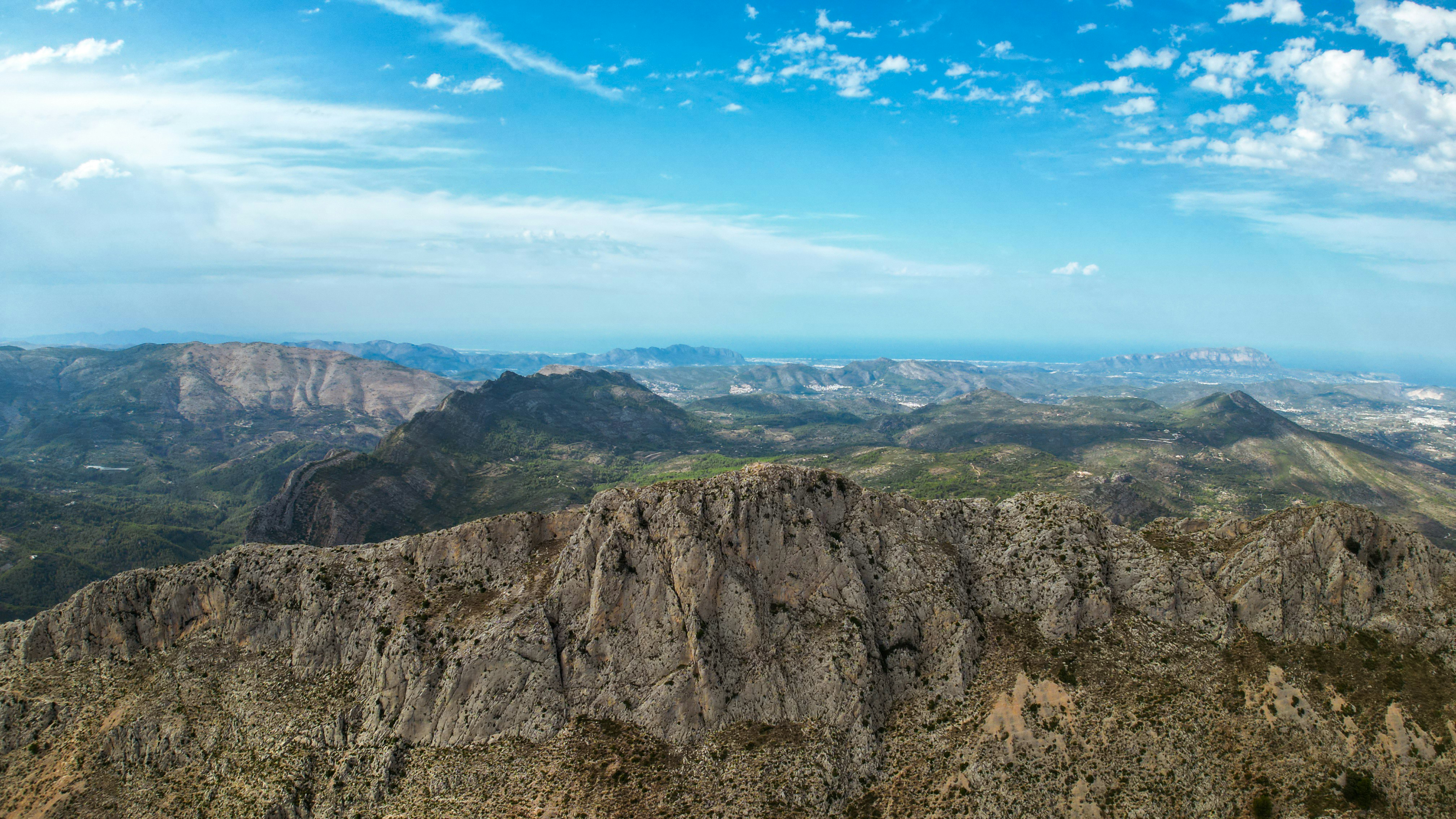 Drone view of Serra de Bèrnia, Spain | Mountain range under a bright, blue sky.