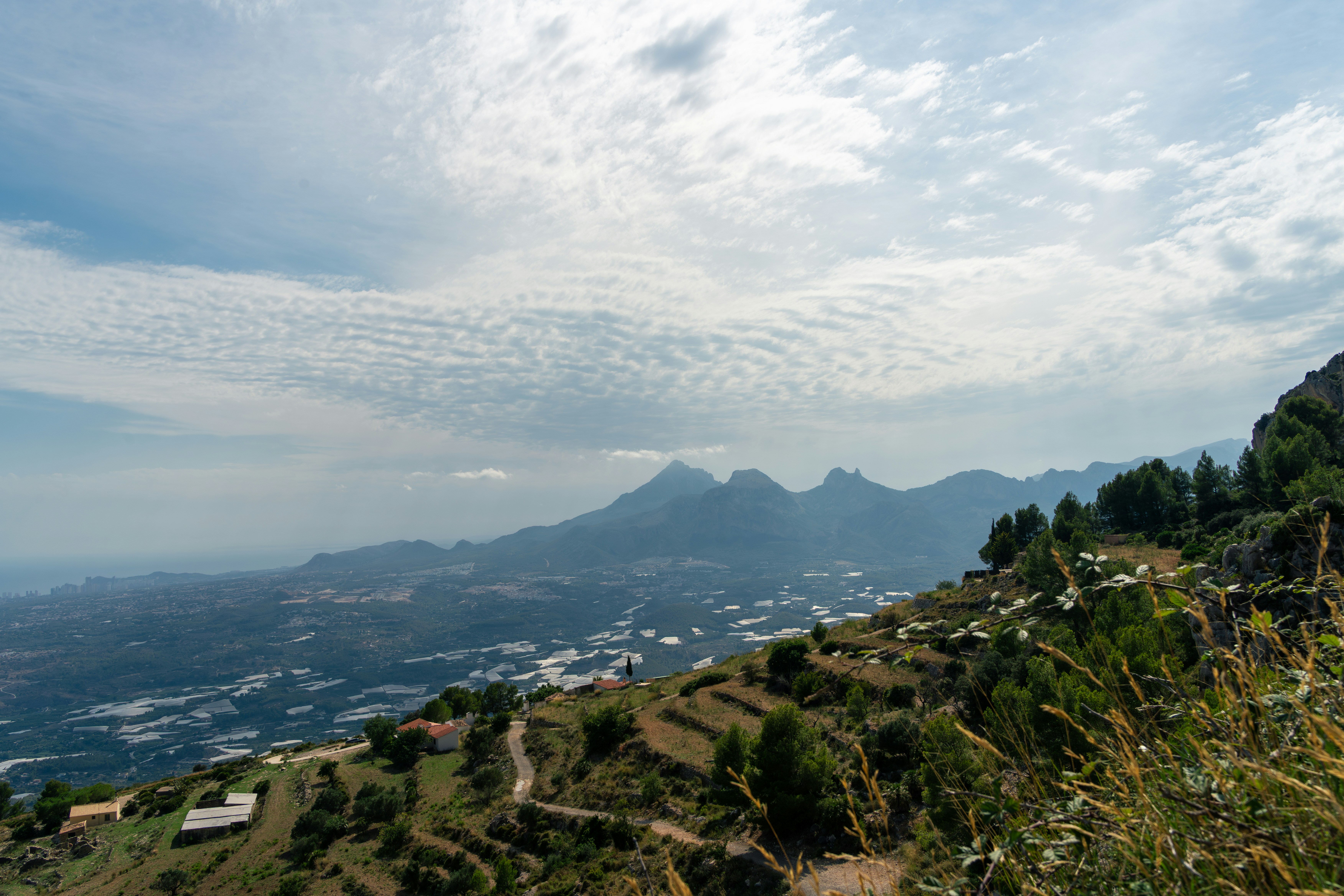 Serra de Bèrnia, Spain | Mountains and a valley are seen under a cloudy sky.