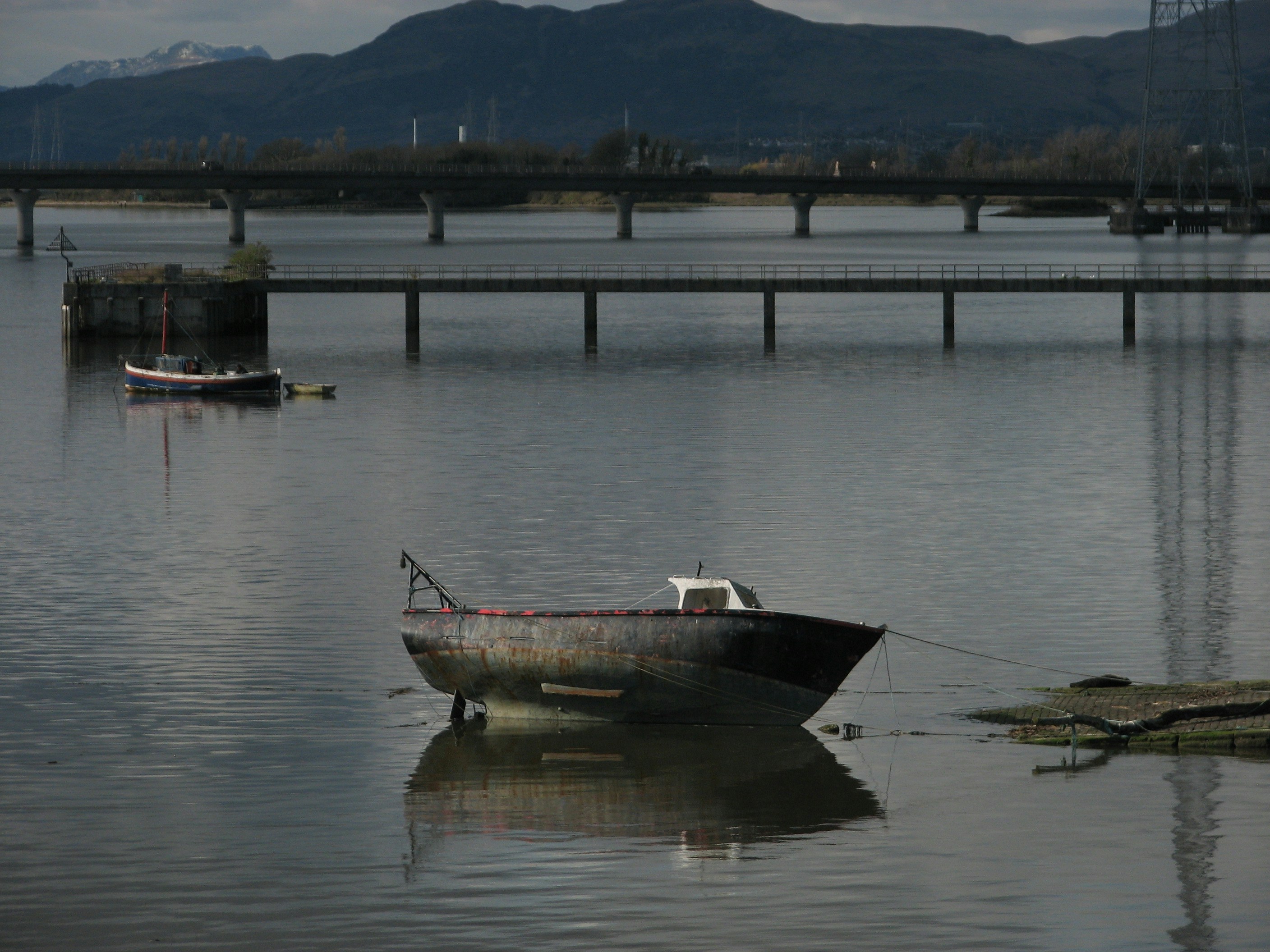 Boats float on water beneath a bridge.
