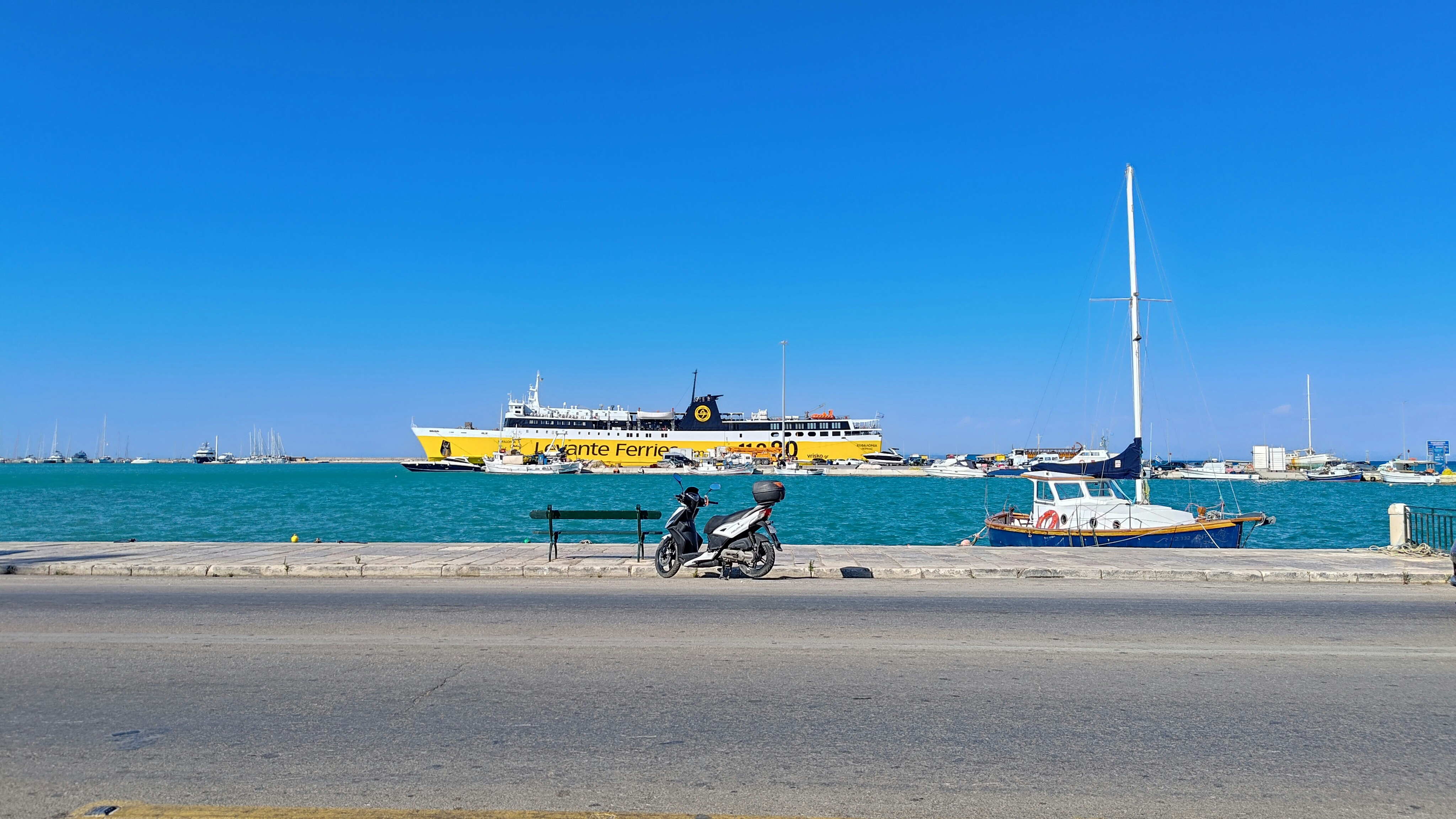 A ferry and sailboats on a clear blue sea.