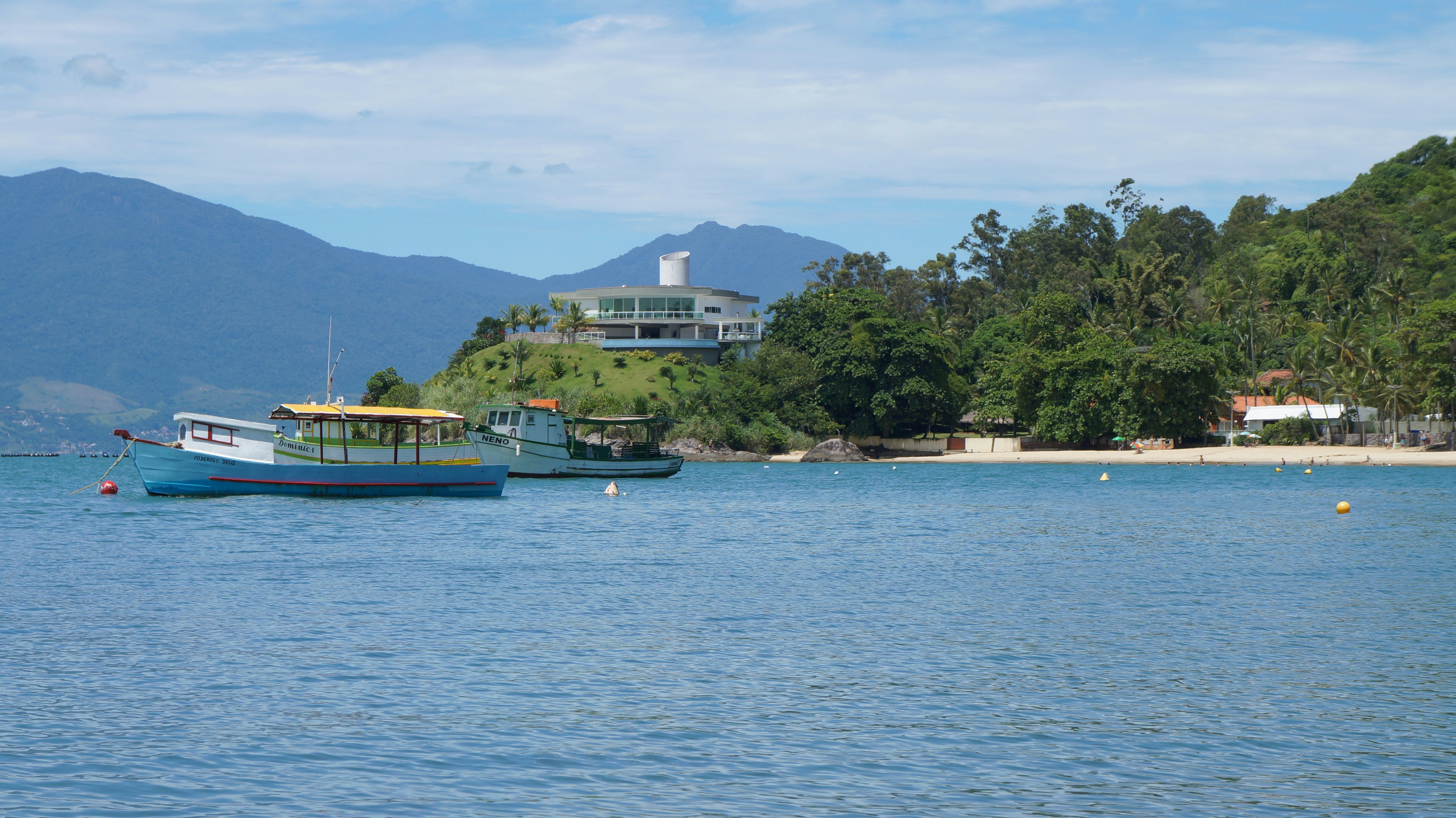 Boats float near a lush coast and mountains.