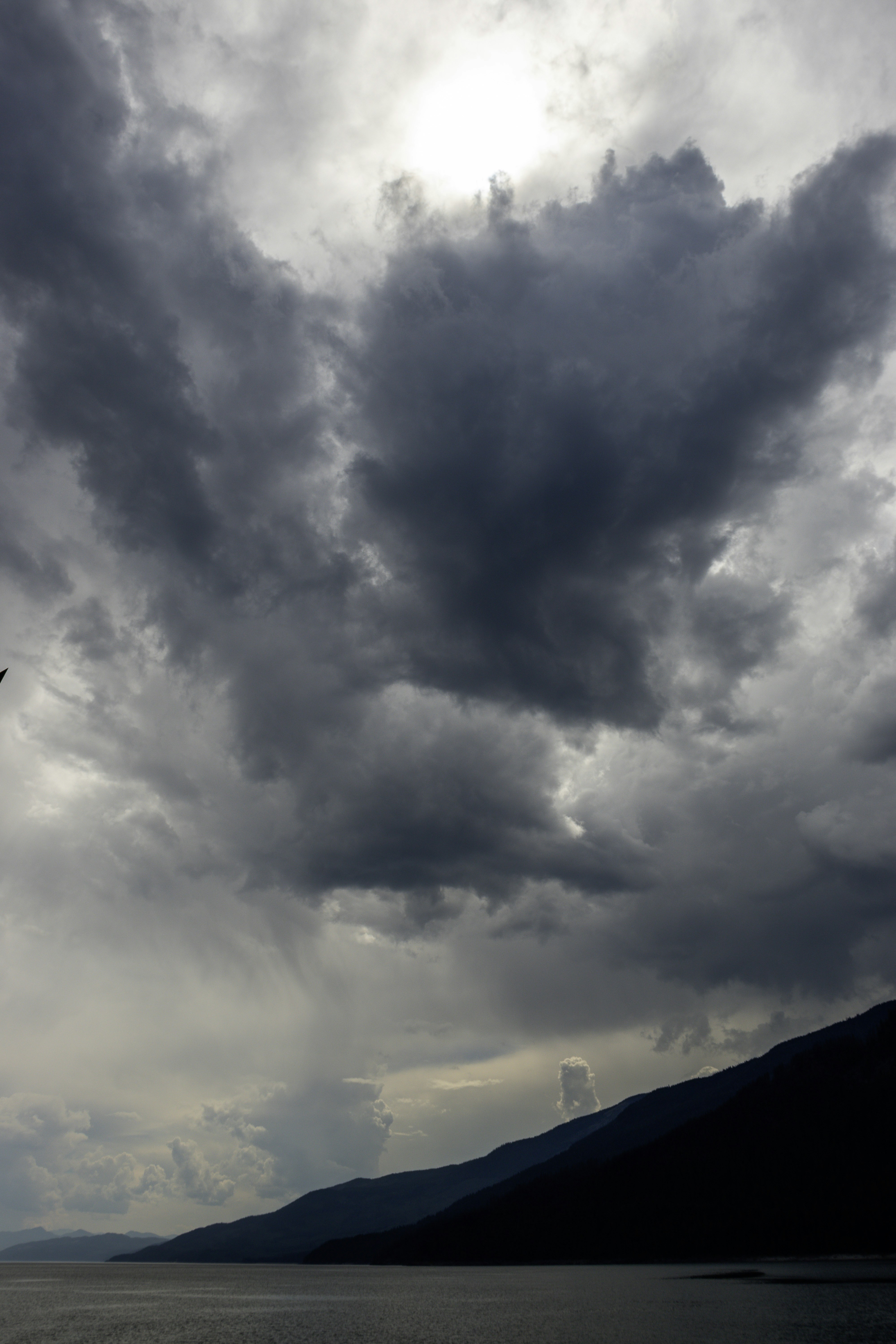 Canada British Columbia Selkird Mountain Ranges Upper and Lower Arrow Lake ferries. | Dark, cloudy sky over a body of water.