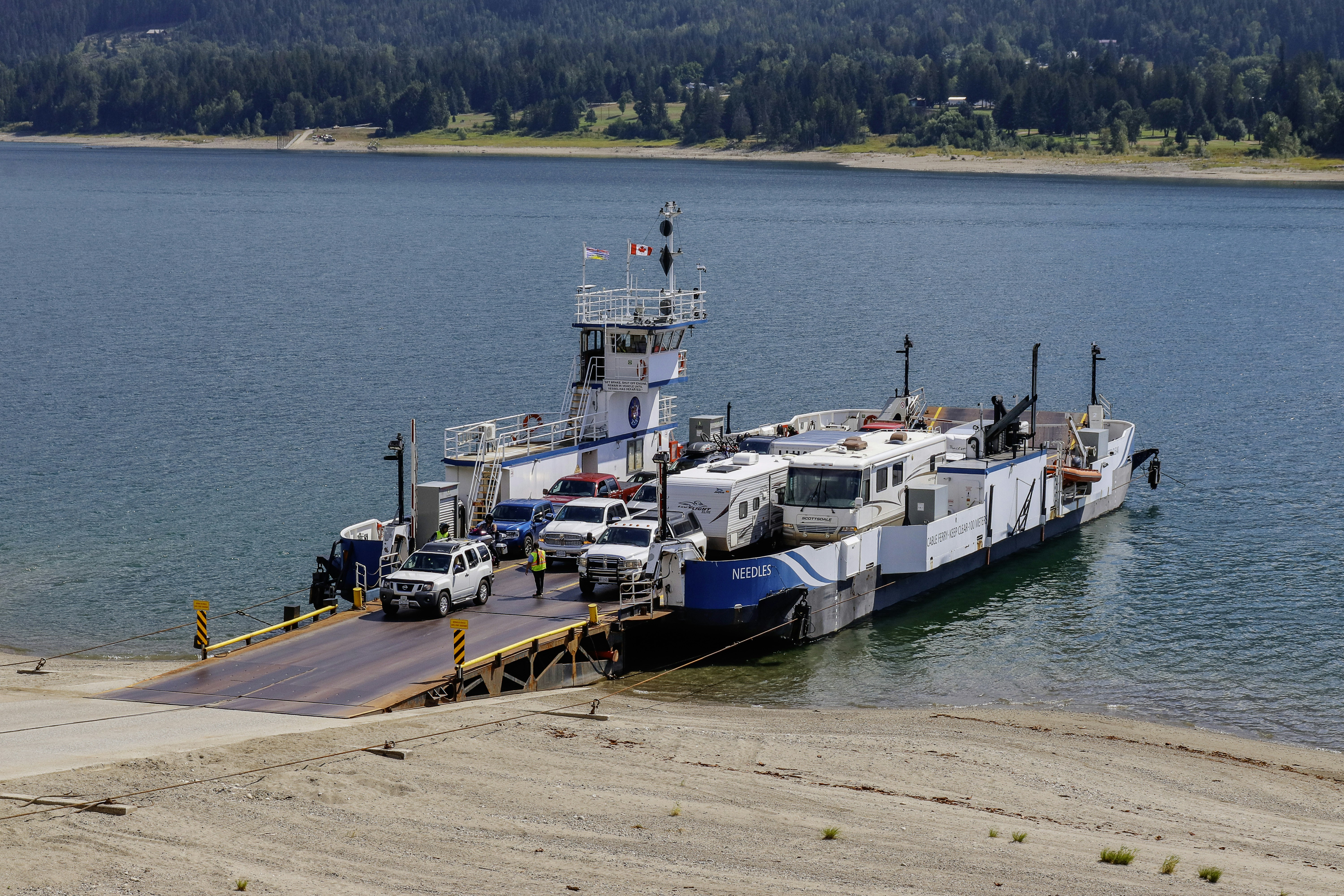 Canada British Columbia Selkirk Mountain Ranges Upper and Lower Arrow Lake ferries. | Cars are boarding a ferry on a lake.