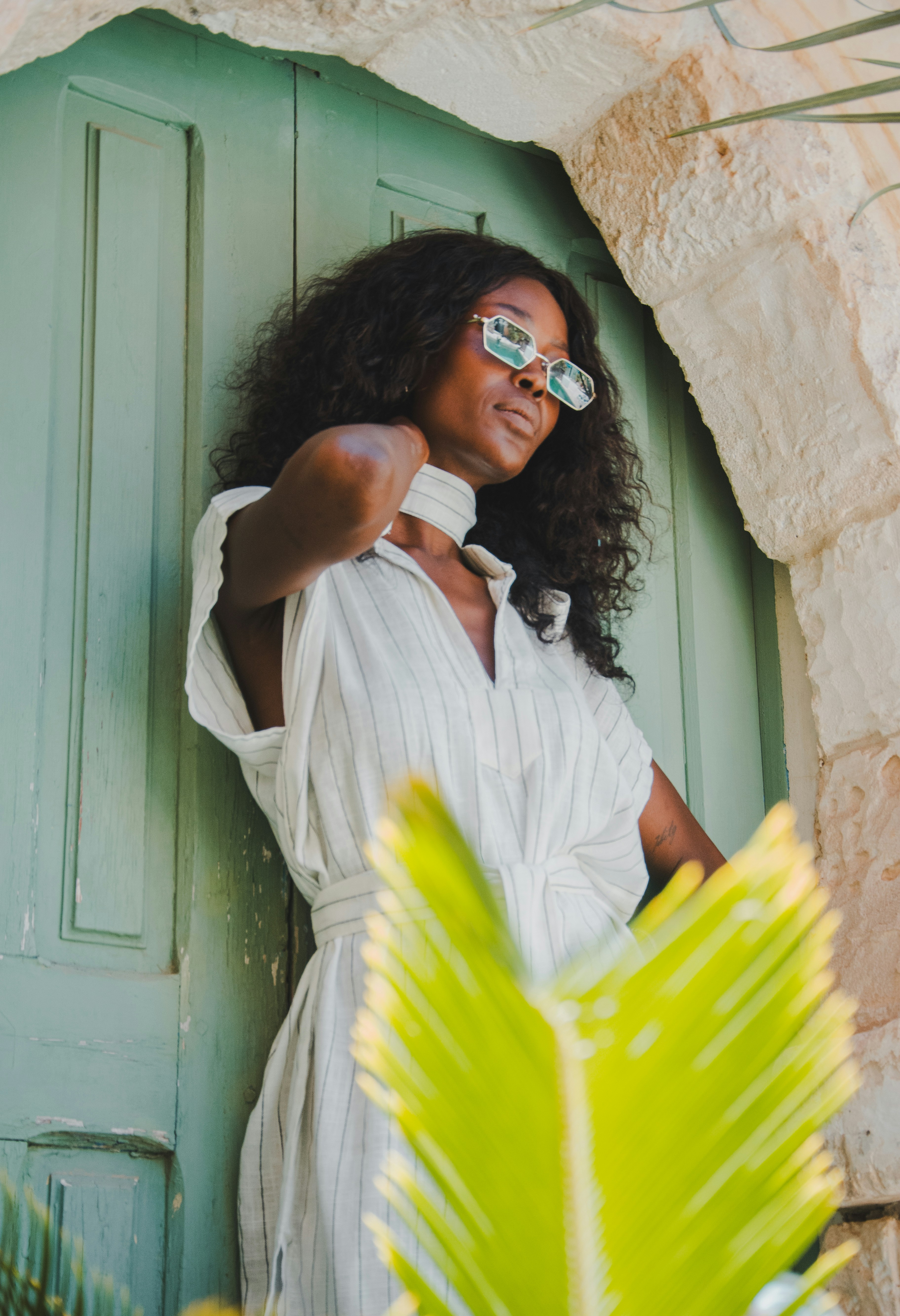 Fashion portrait of a model wearing a trendy short dress. | A woman poses near a green door.