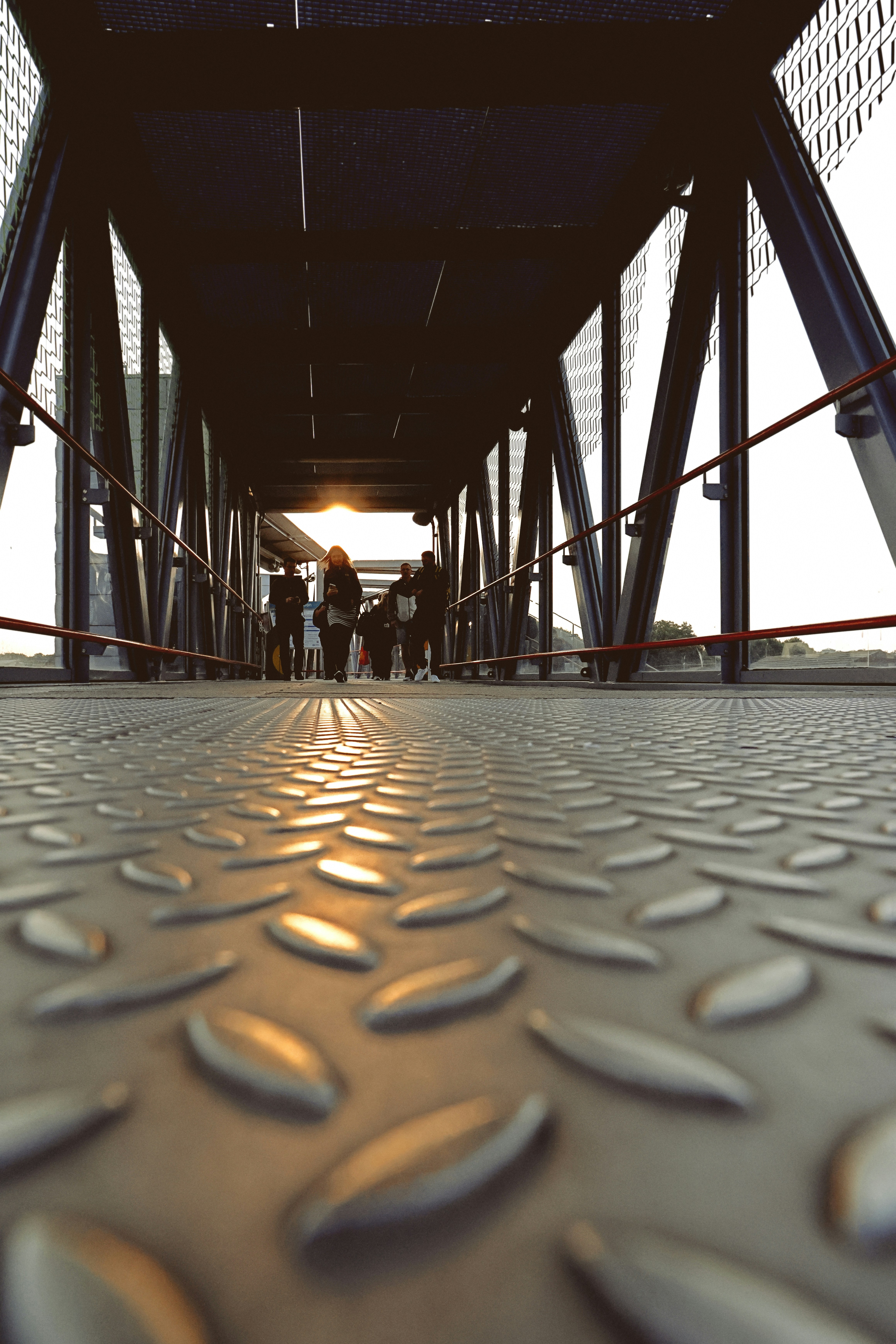 People walk across a metal bridge in sunlight. photo – Free Street ...