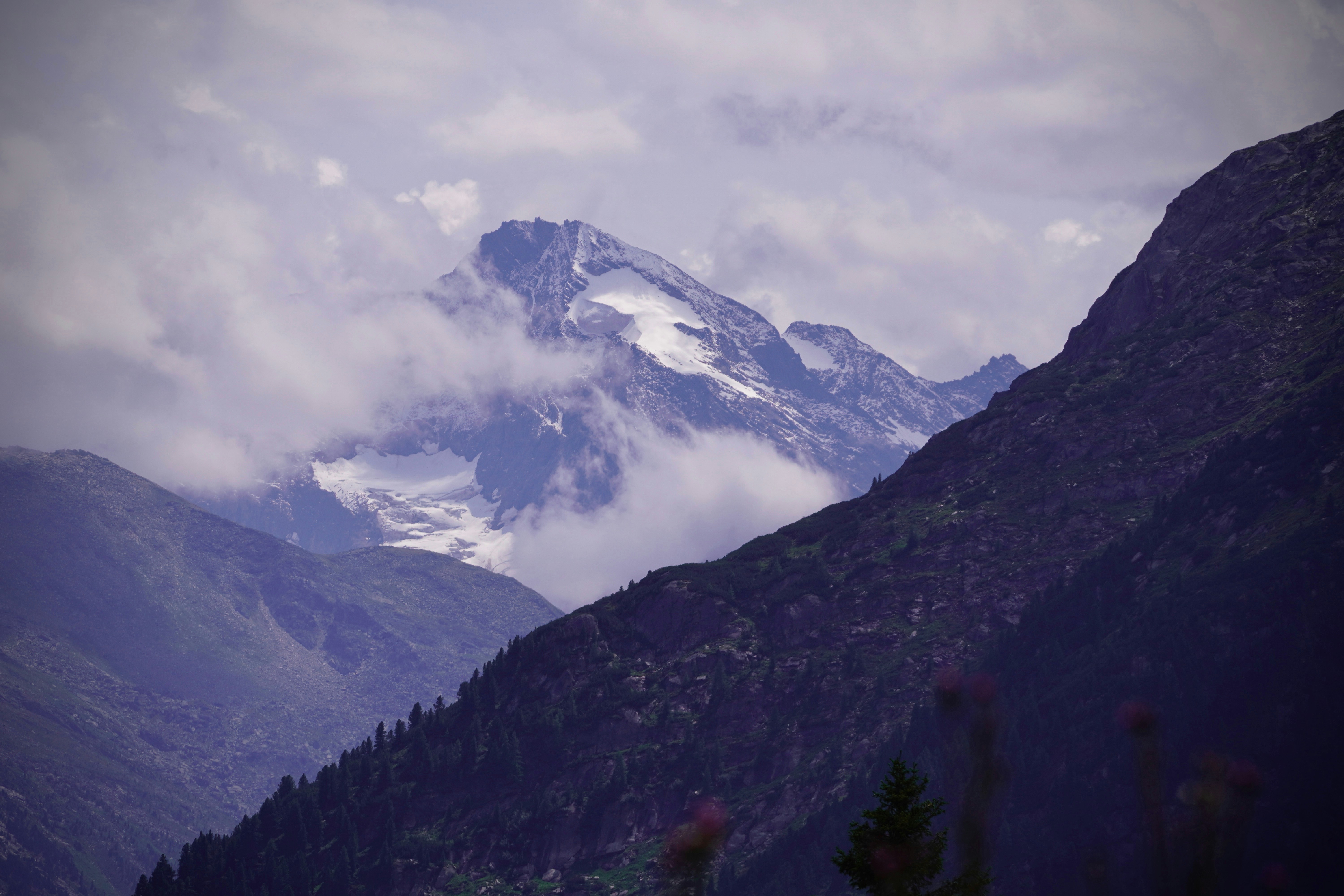 Snow-capped mountain peak peeks through the clouds.