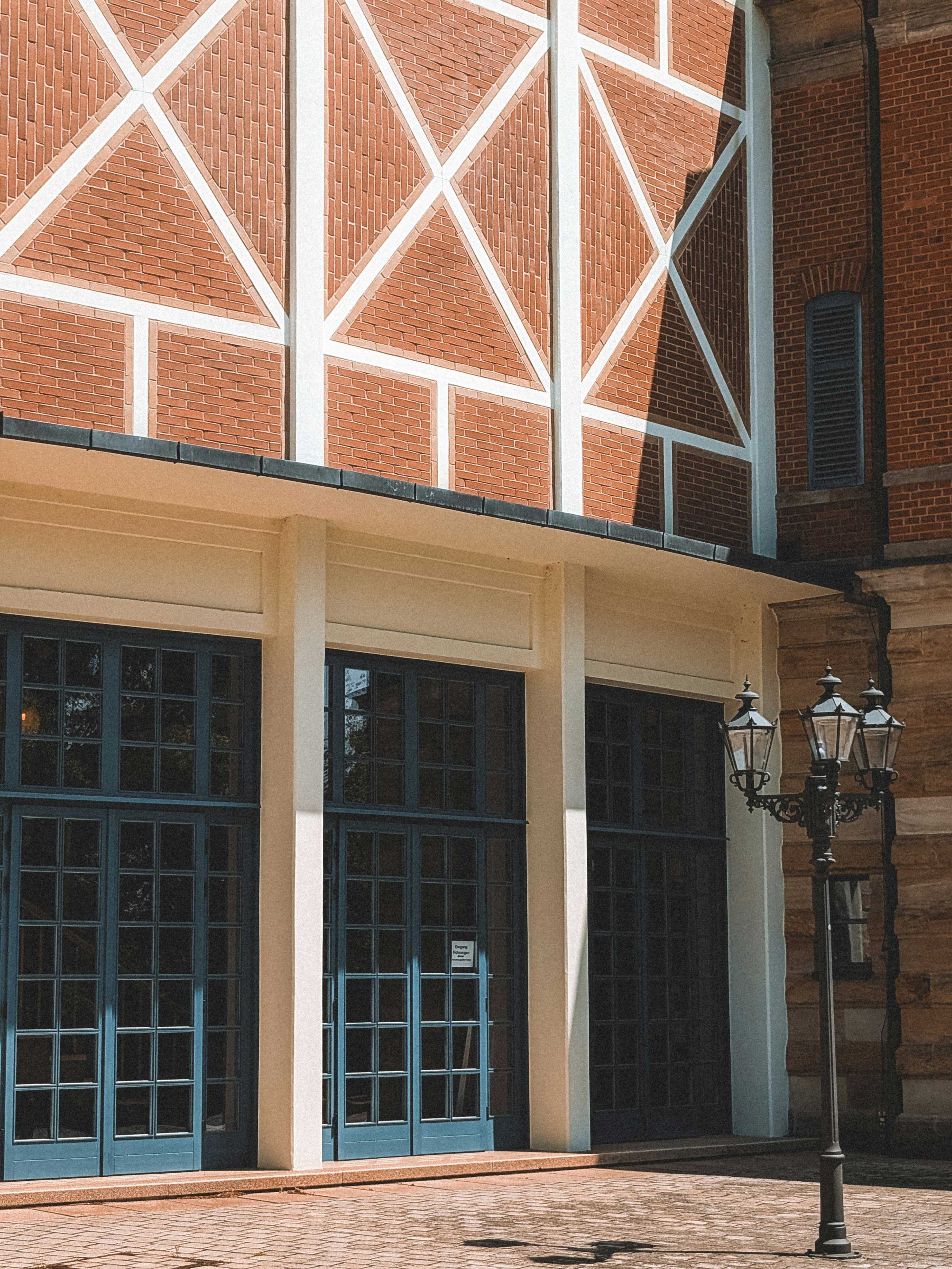 Close-up of the geometric red-brick lattice | Building facade with windows and decorative brickwork.