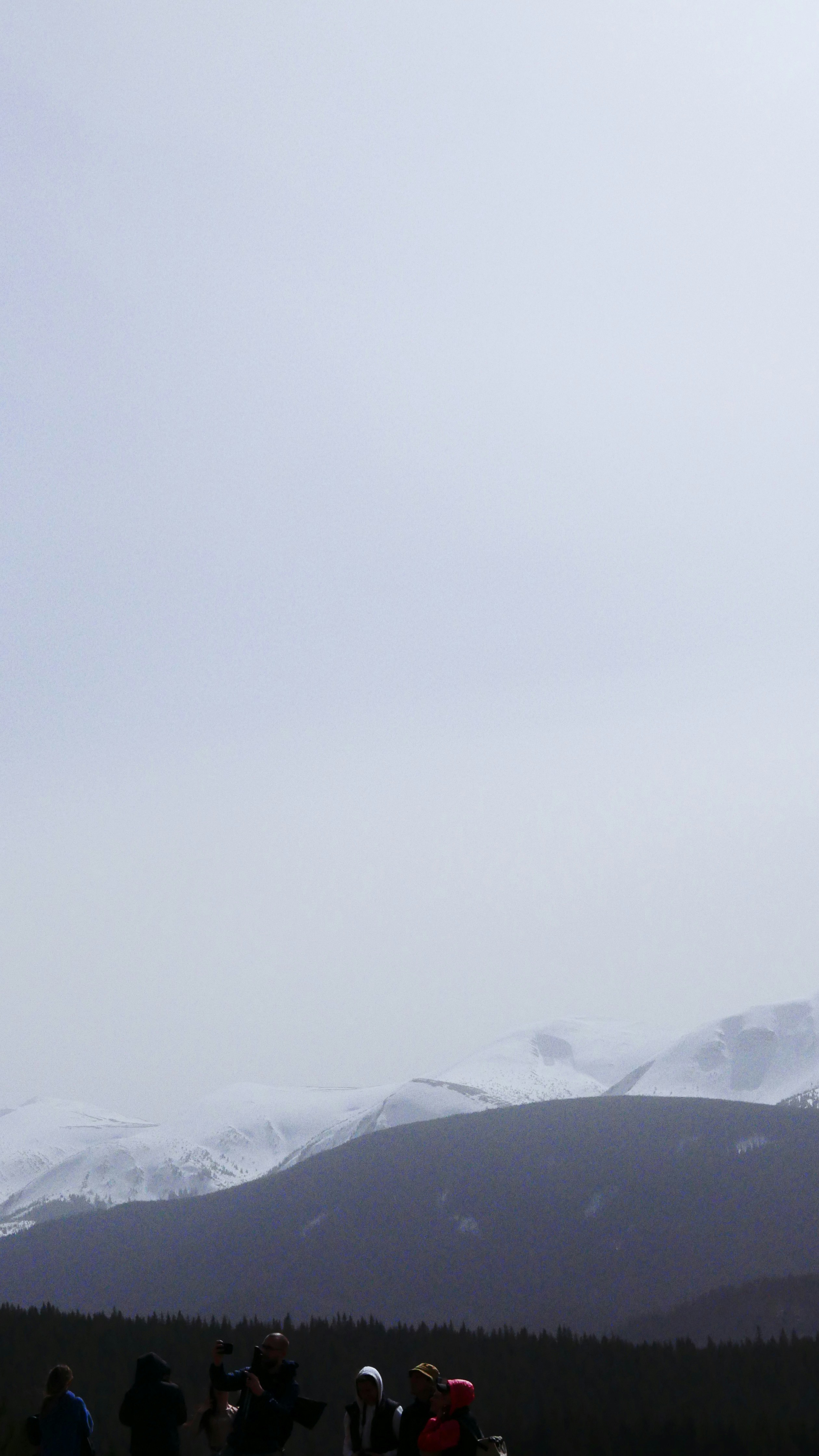 Snow-capped mountains loom in the distance, with a group of individuals gathered in the foreground, immersed in the serene winter landscape.