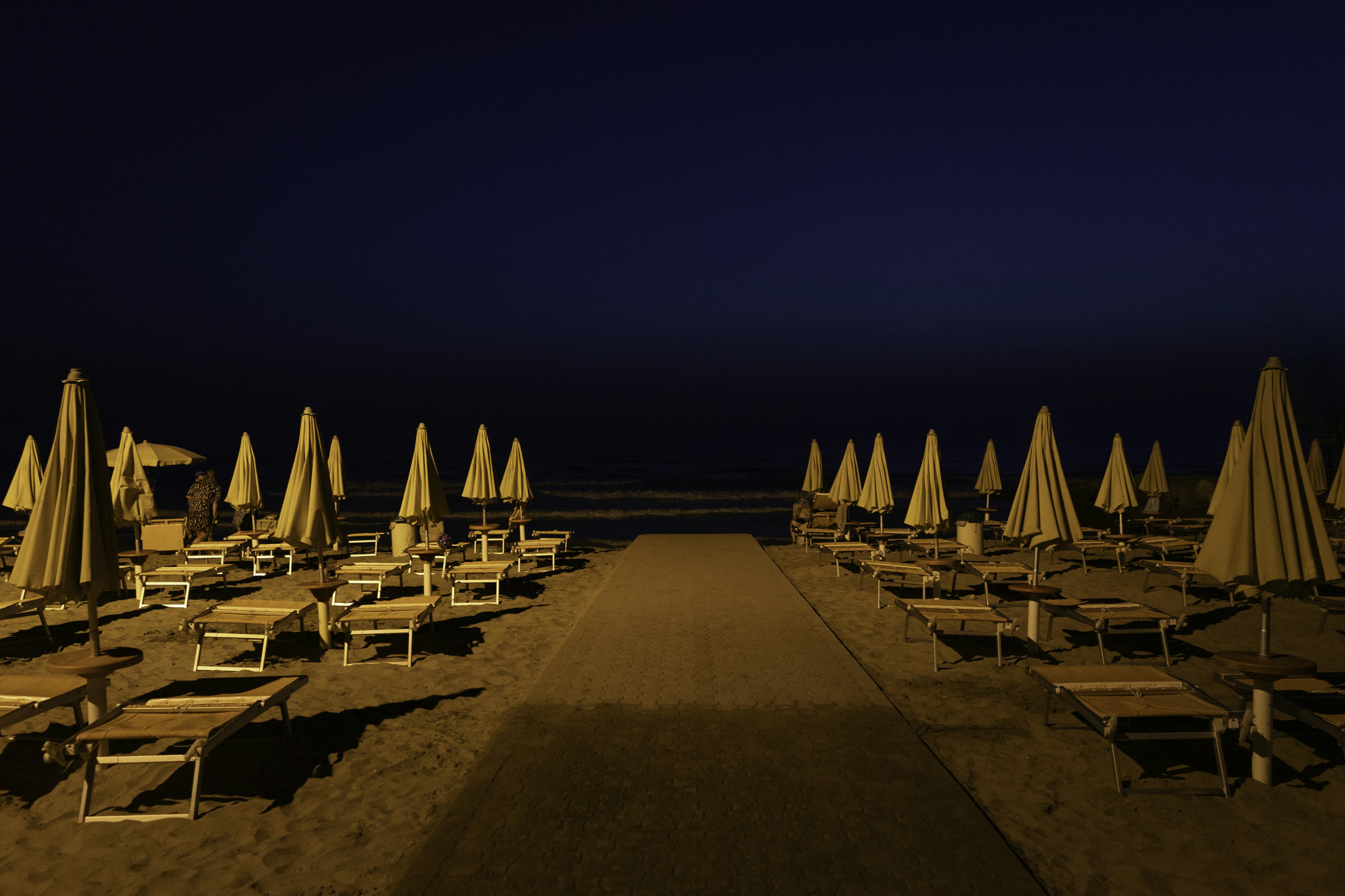 Empty beach with chairs and umbrellas at night.