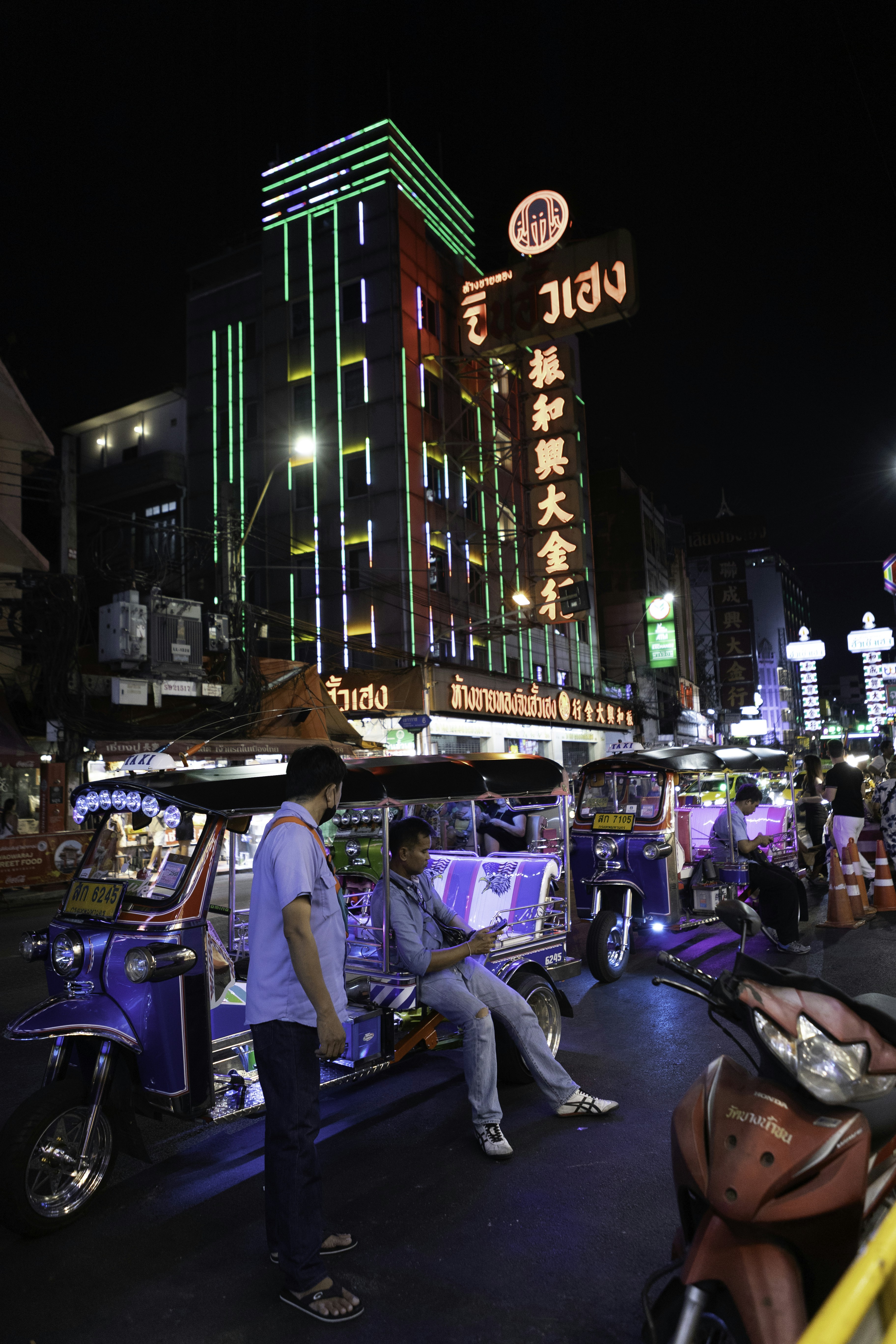 Tuk-tuks and neon signs illuminate a city street at night. photo – Free ...