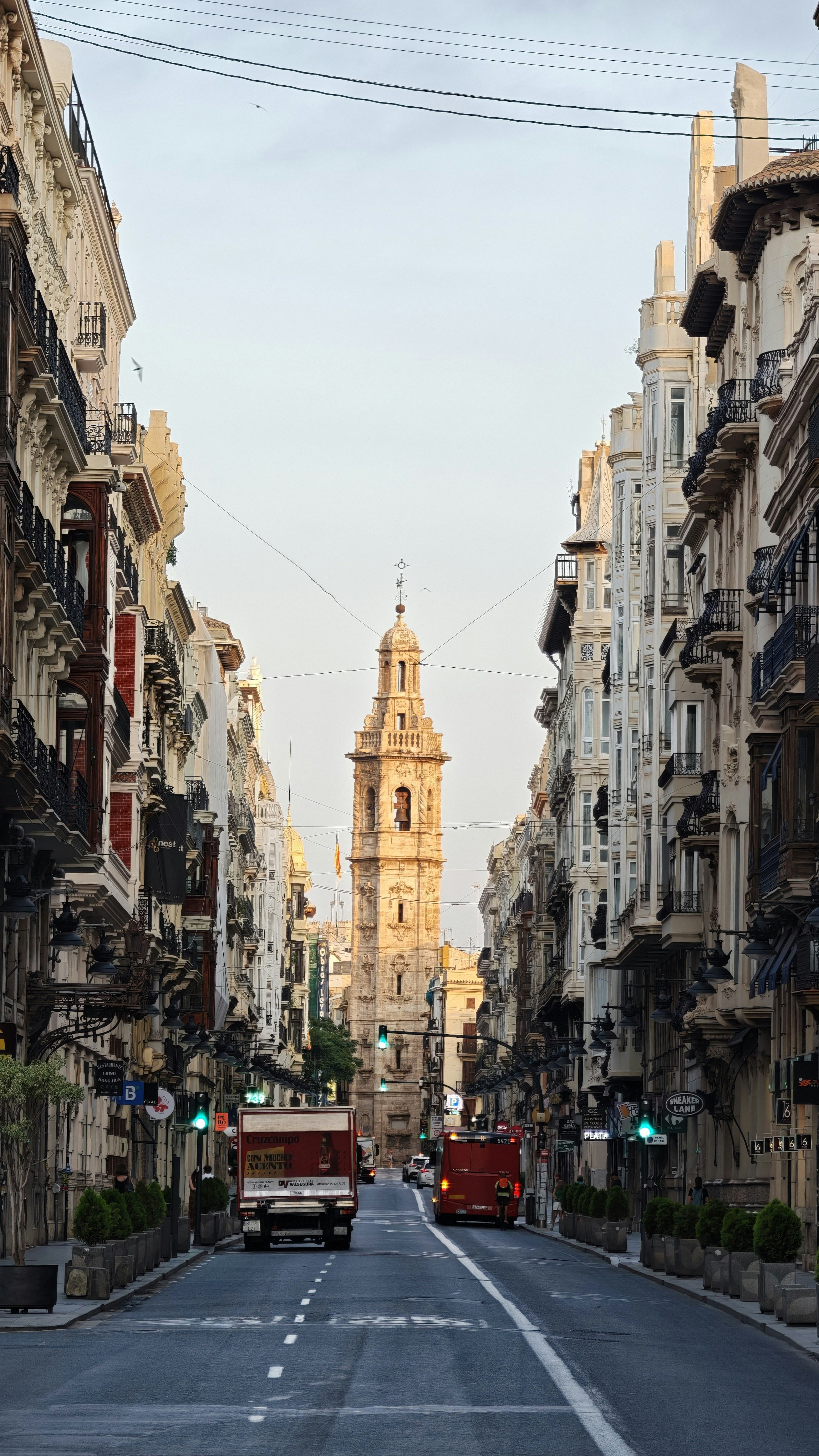 A street view leads to a tall cathedral tower.