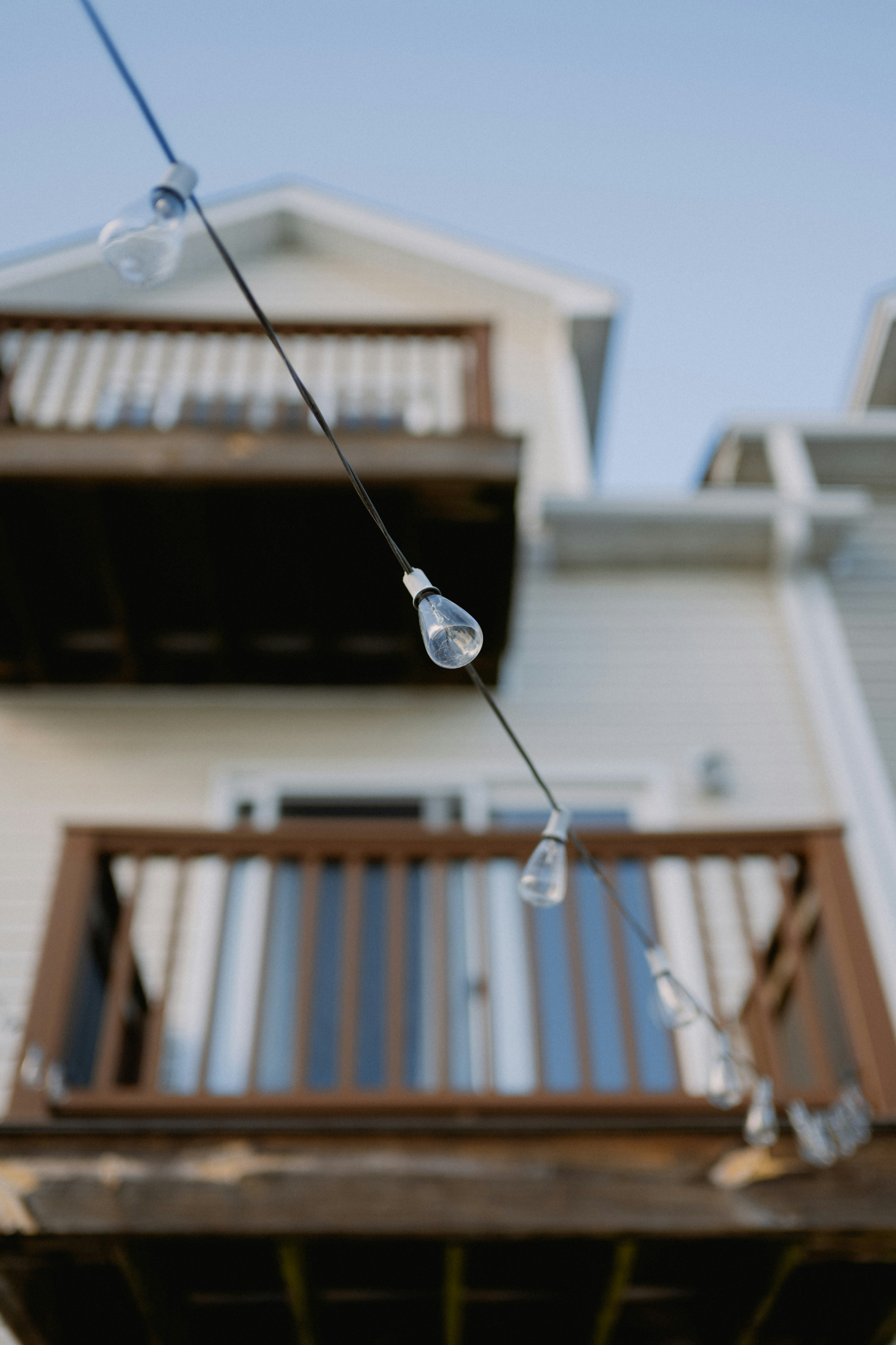 String lights hang against a house with a balcony.