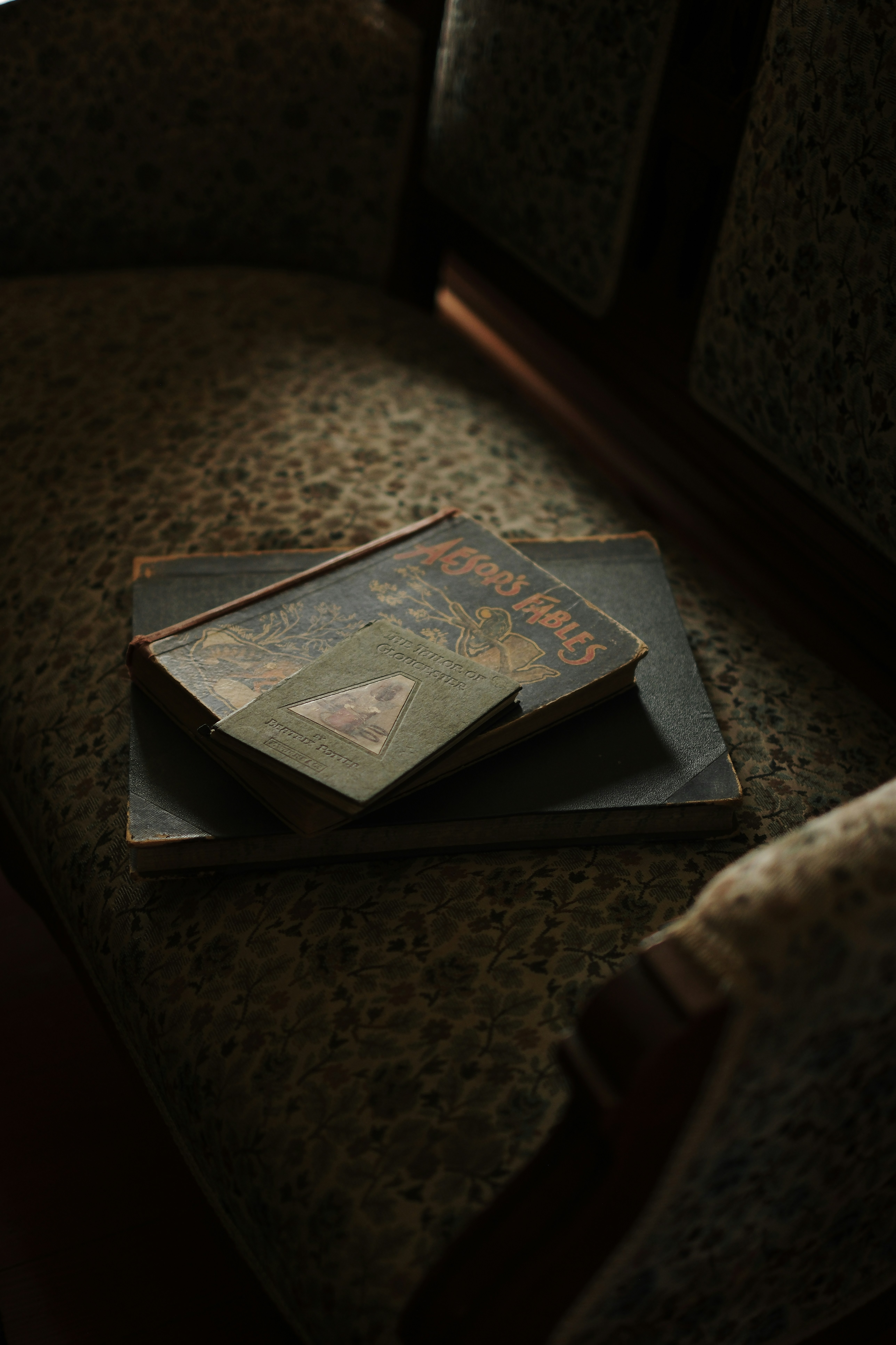 Instagram - @kaprion | Old books are resting on a vintage patterned chair.