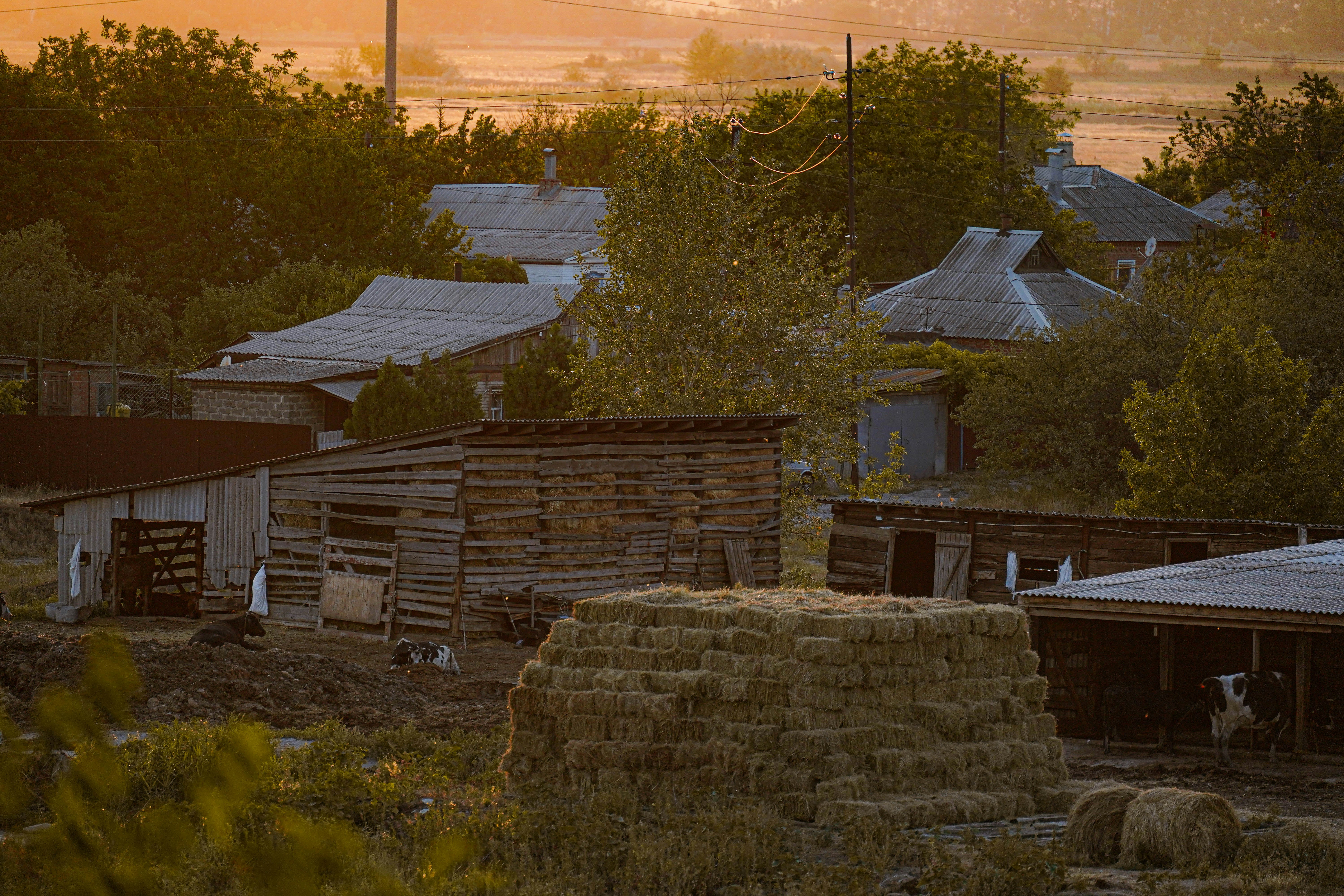 Rural buildings and hay bales at sunset.