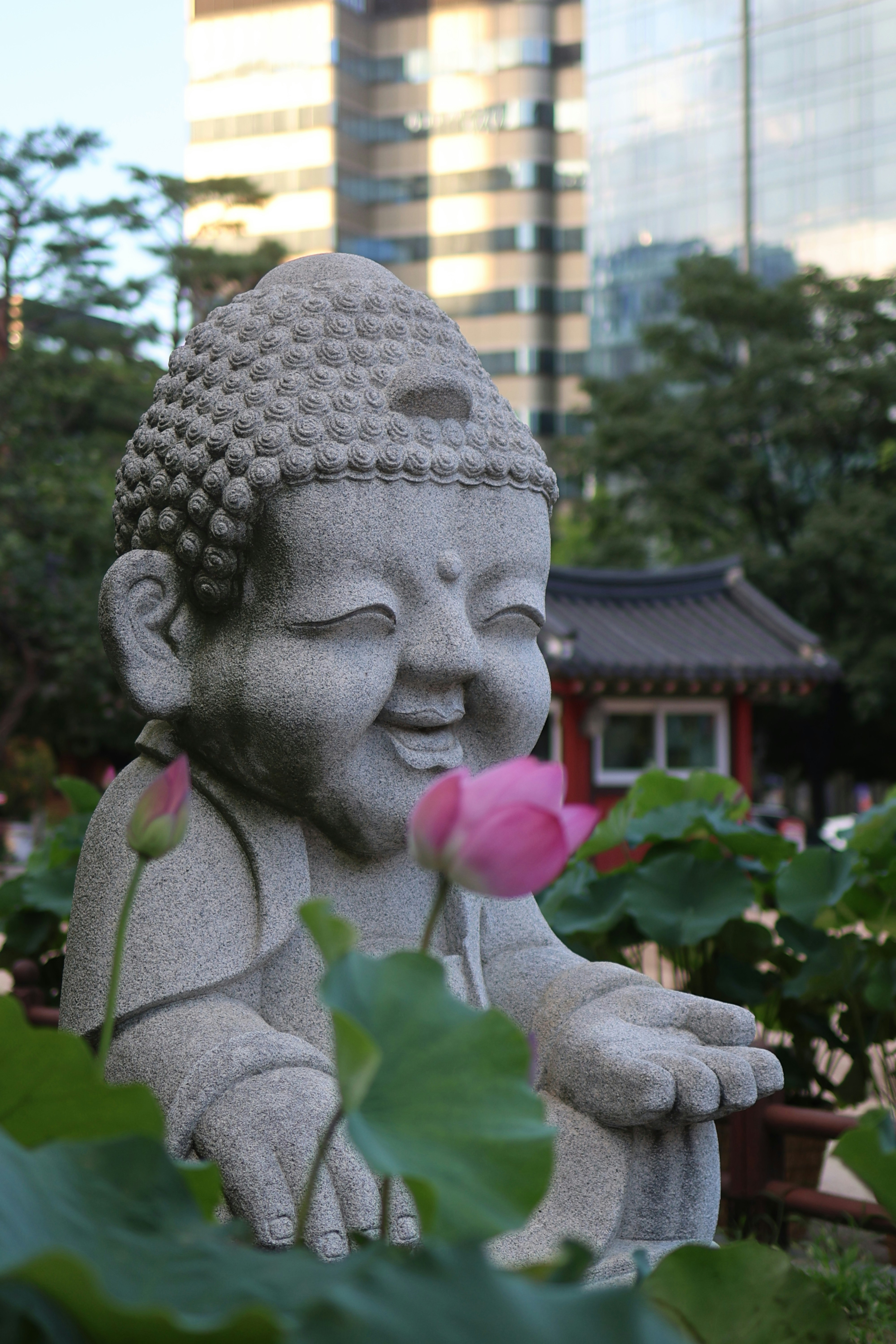 Smiling buddha statue with a lotus flower.