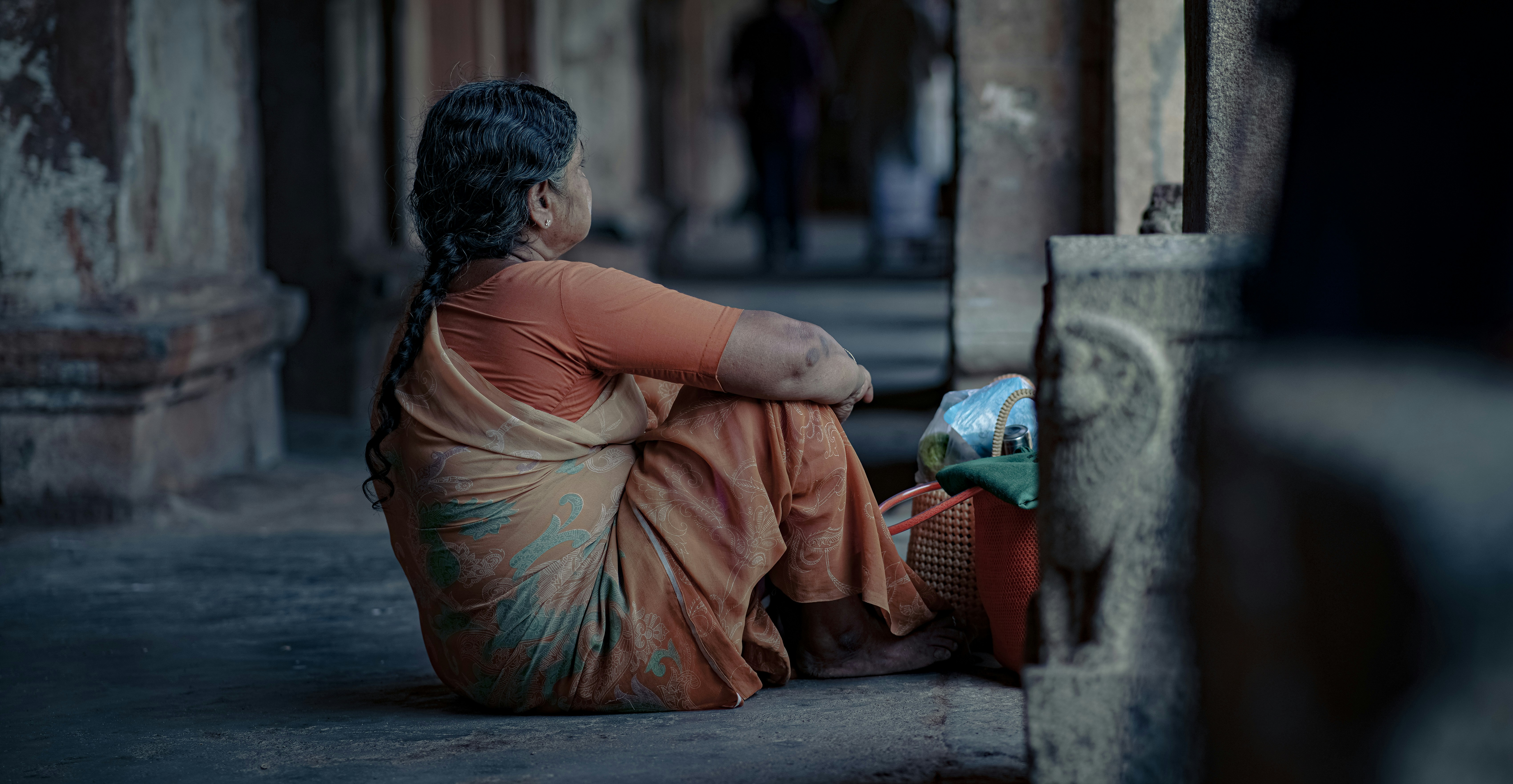 Patience | An elderly woman sits quietly in an ancient structure.