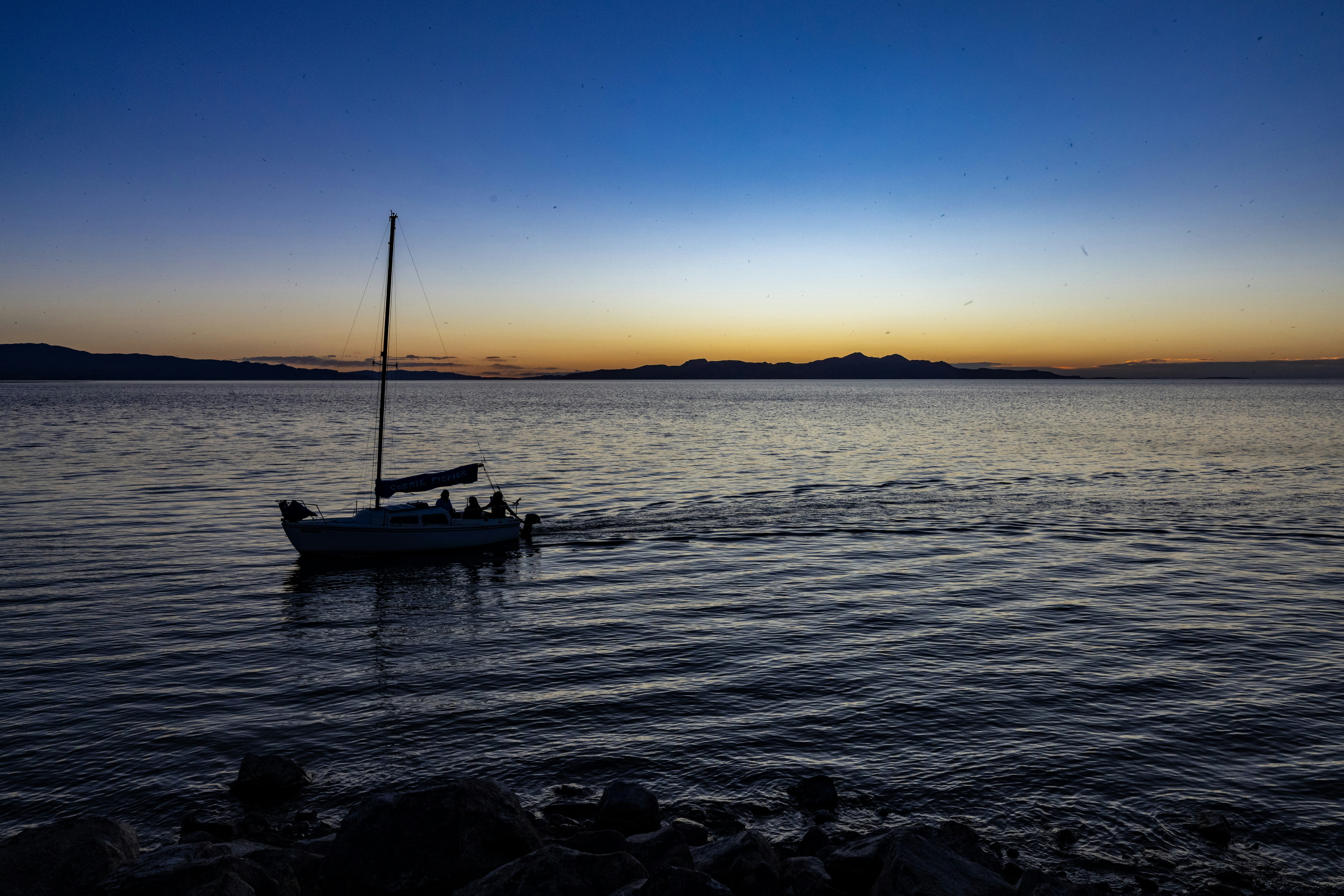 Heading into port just before dark. | A boat sails across the water at dusk.