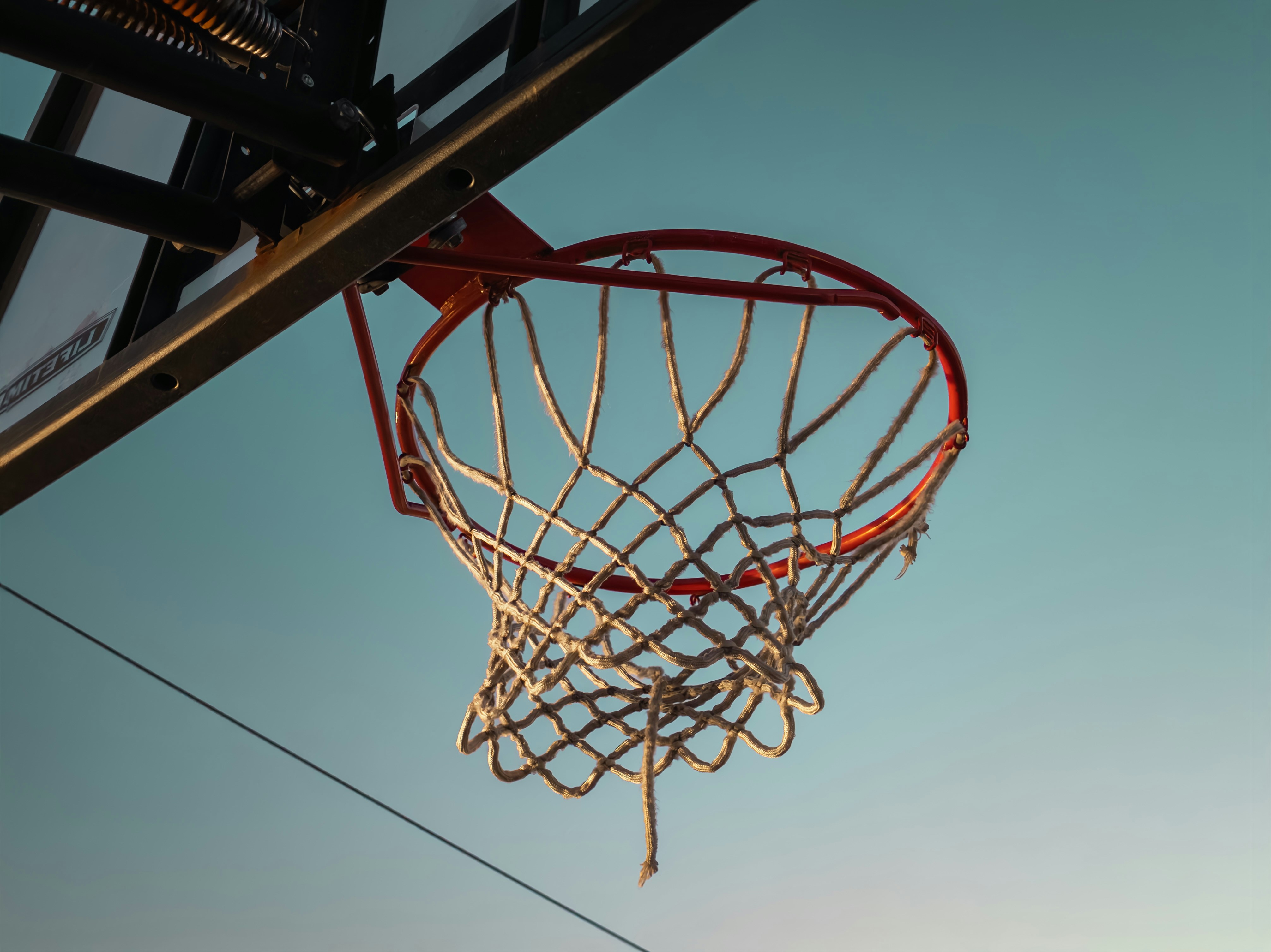 A basketball hoop against a bright sky.