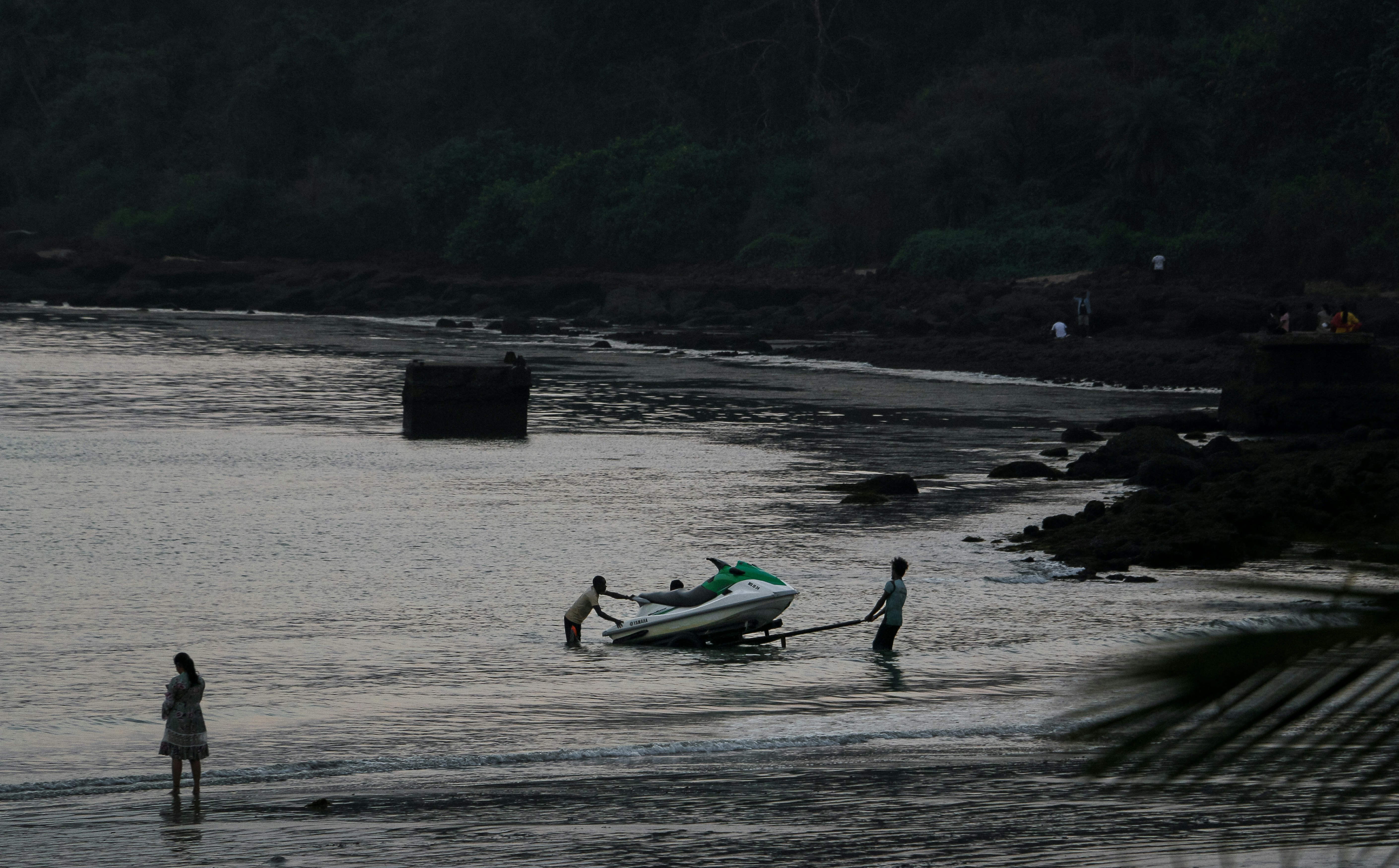 People are moving a jet ski towards the water.