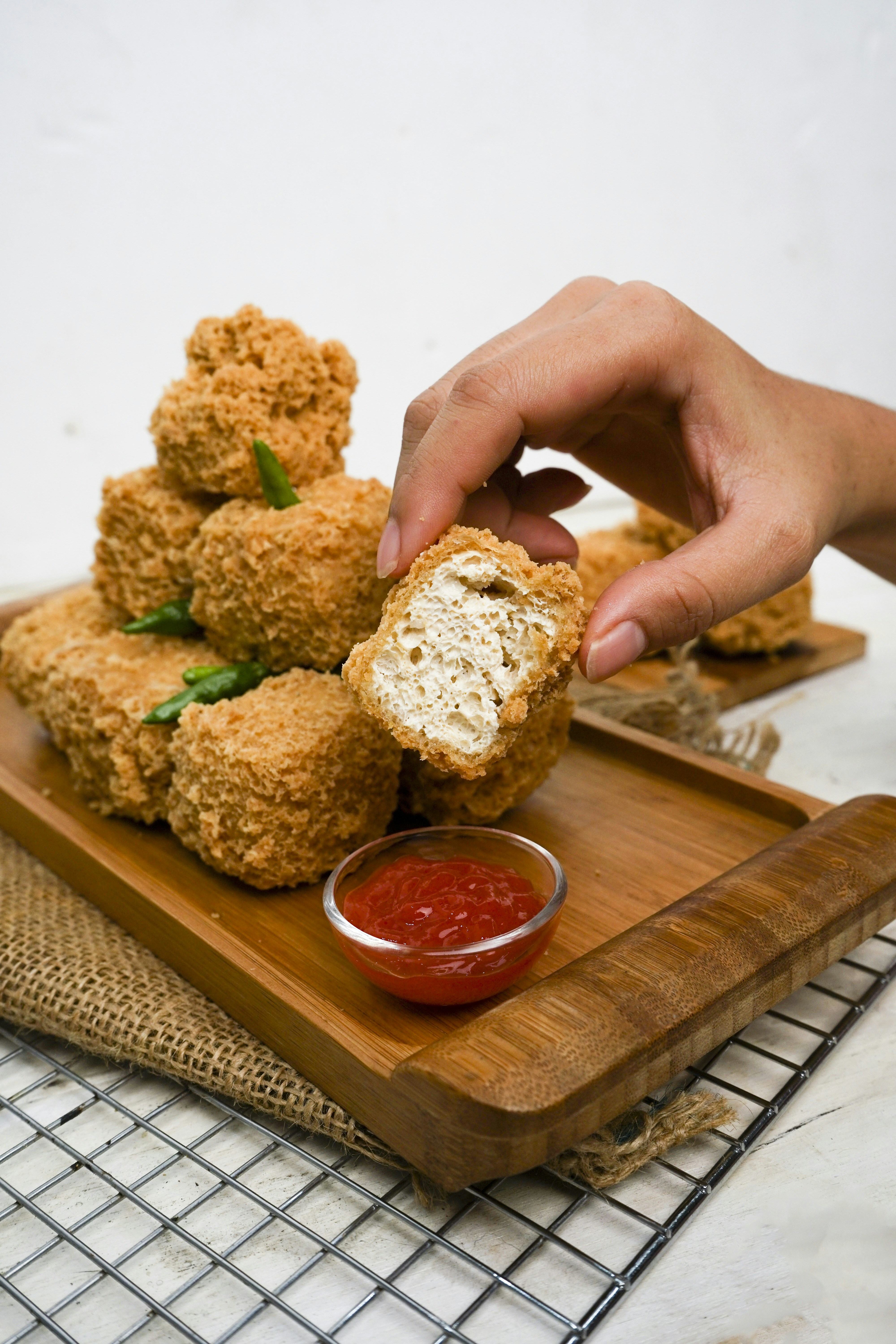 Fried tofu with dipping sauce is being held.