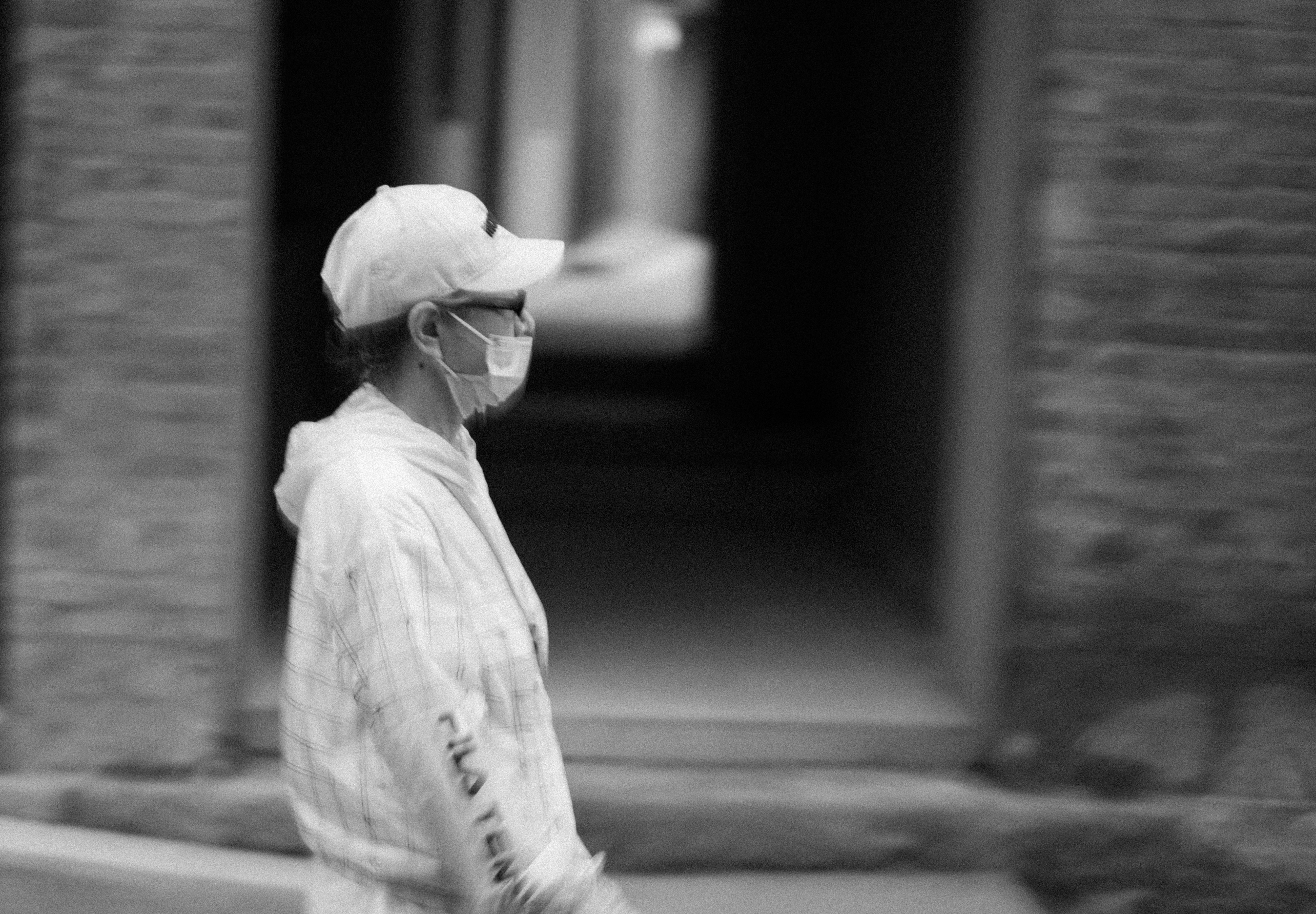 Person wearing a mask walks down a dimly lit alley.