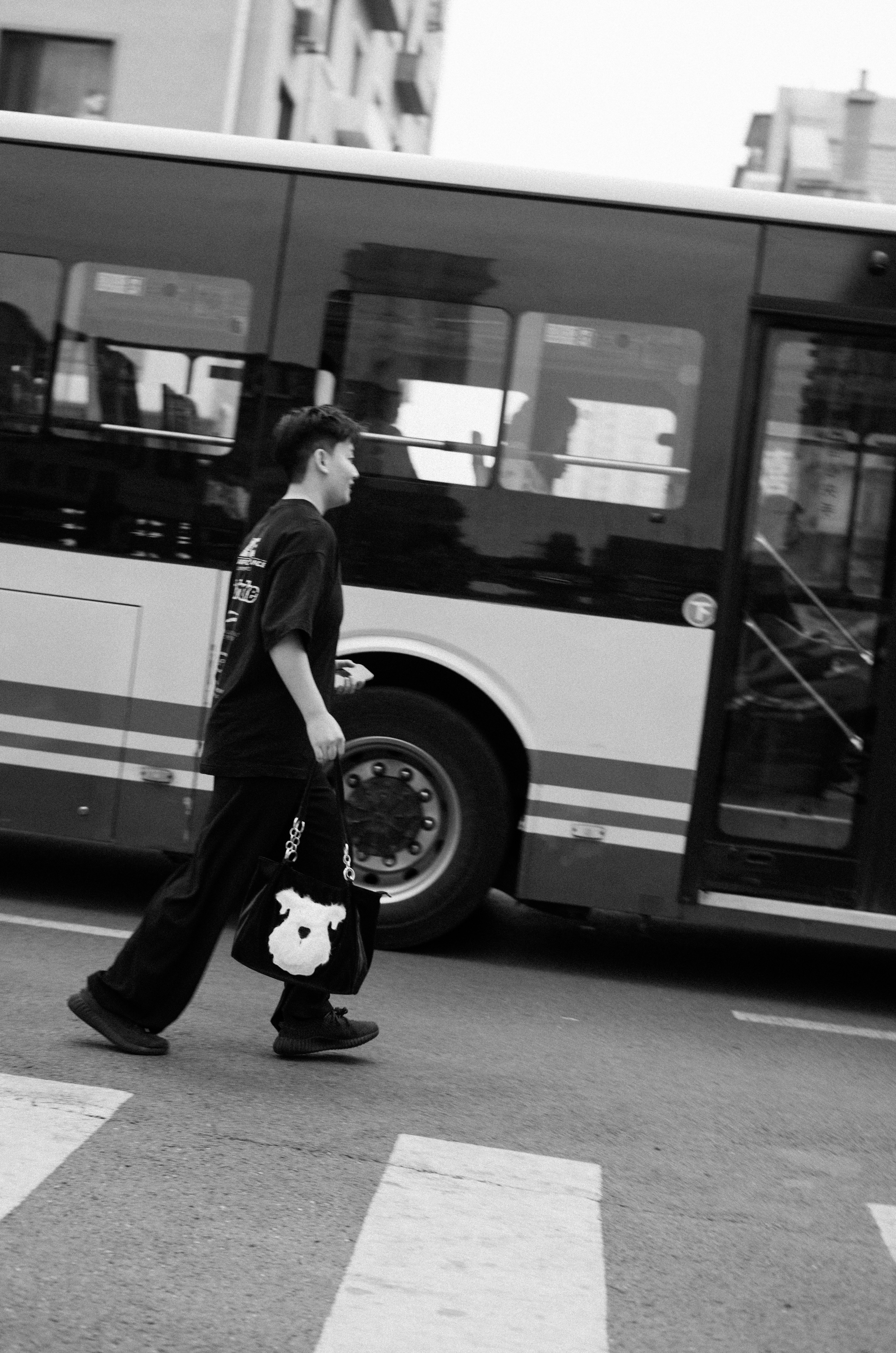 A person crosses the crosswalk near a bus.