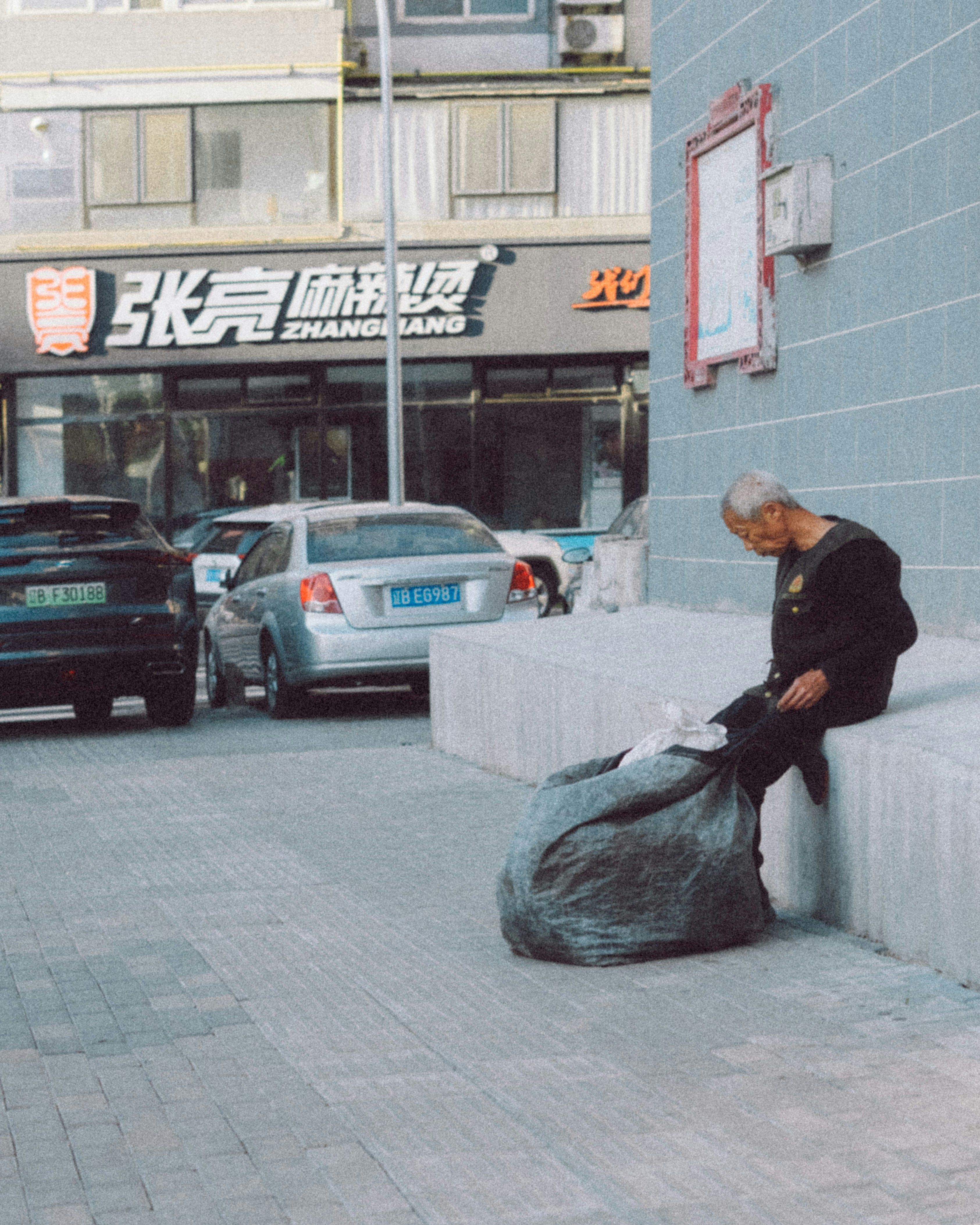 An elderly person rests next to a large bag.