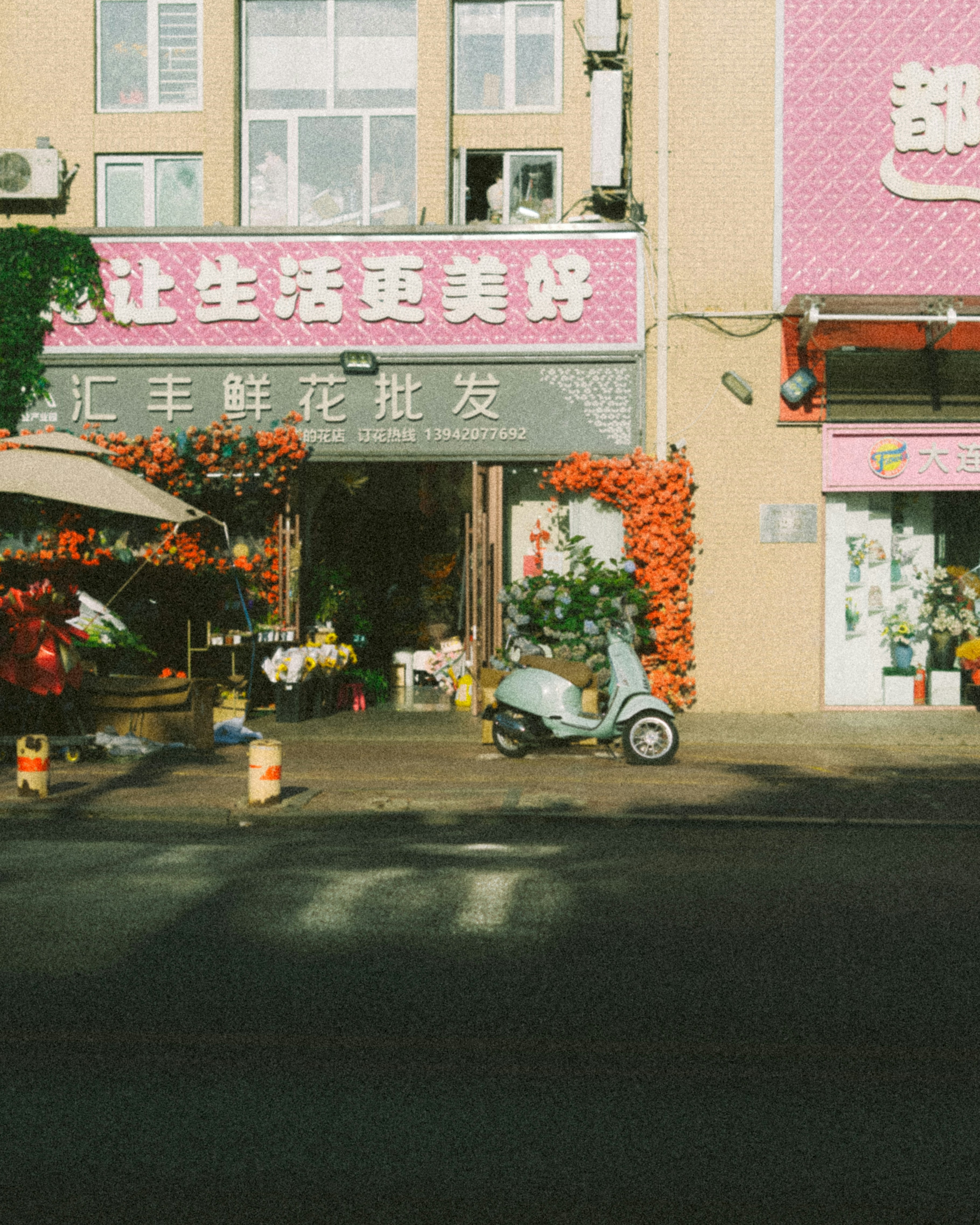 A charming flower shop with a scooter parked outside.