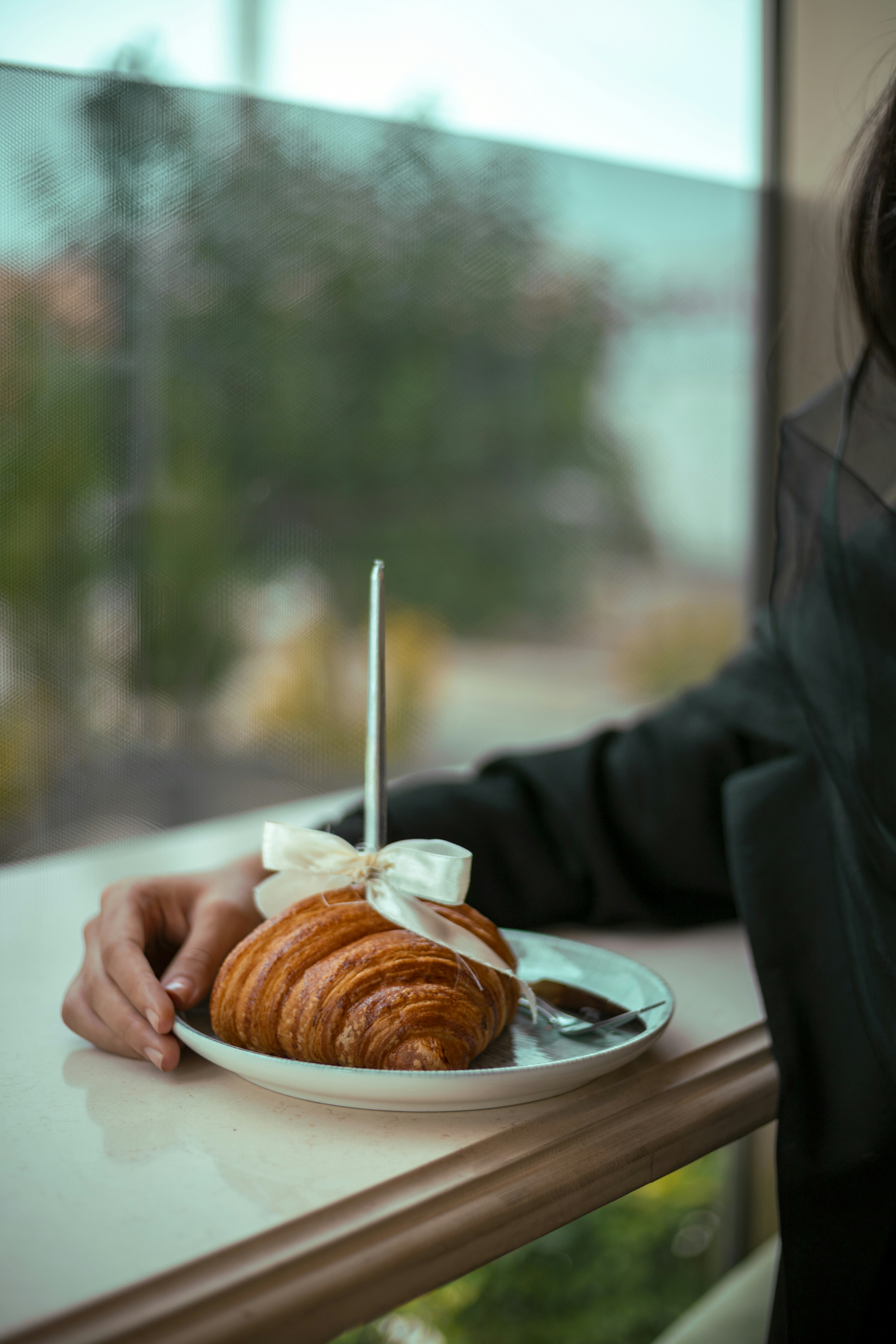 Candle-Stem Croissant at a Window-Side Café