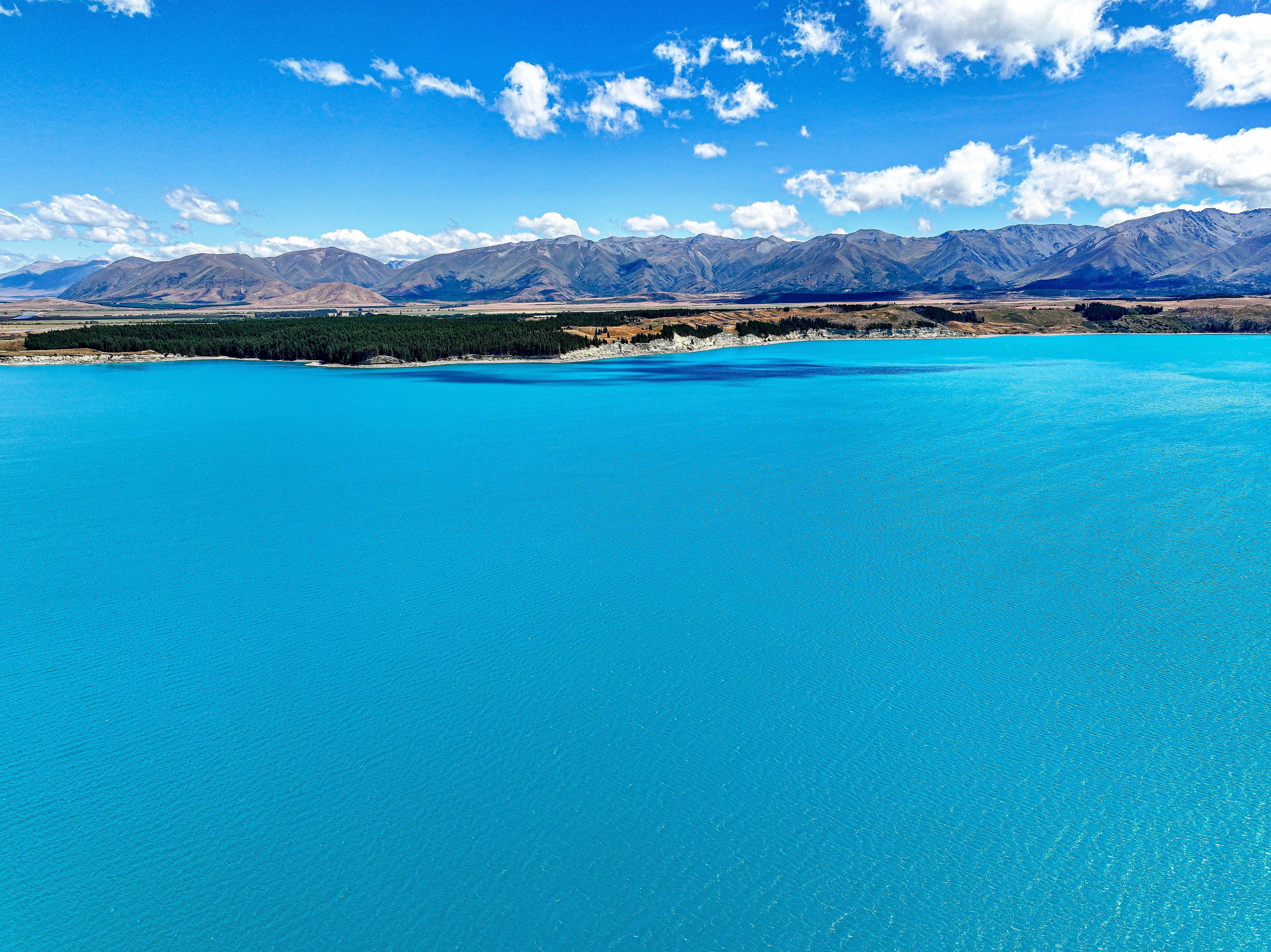 Bright blue lake surrounded by mountains under the sky.