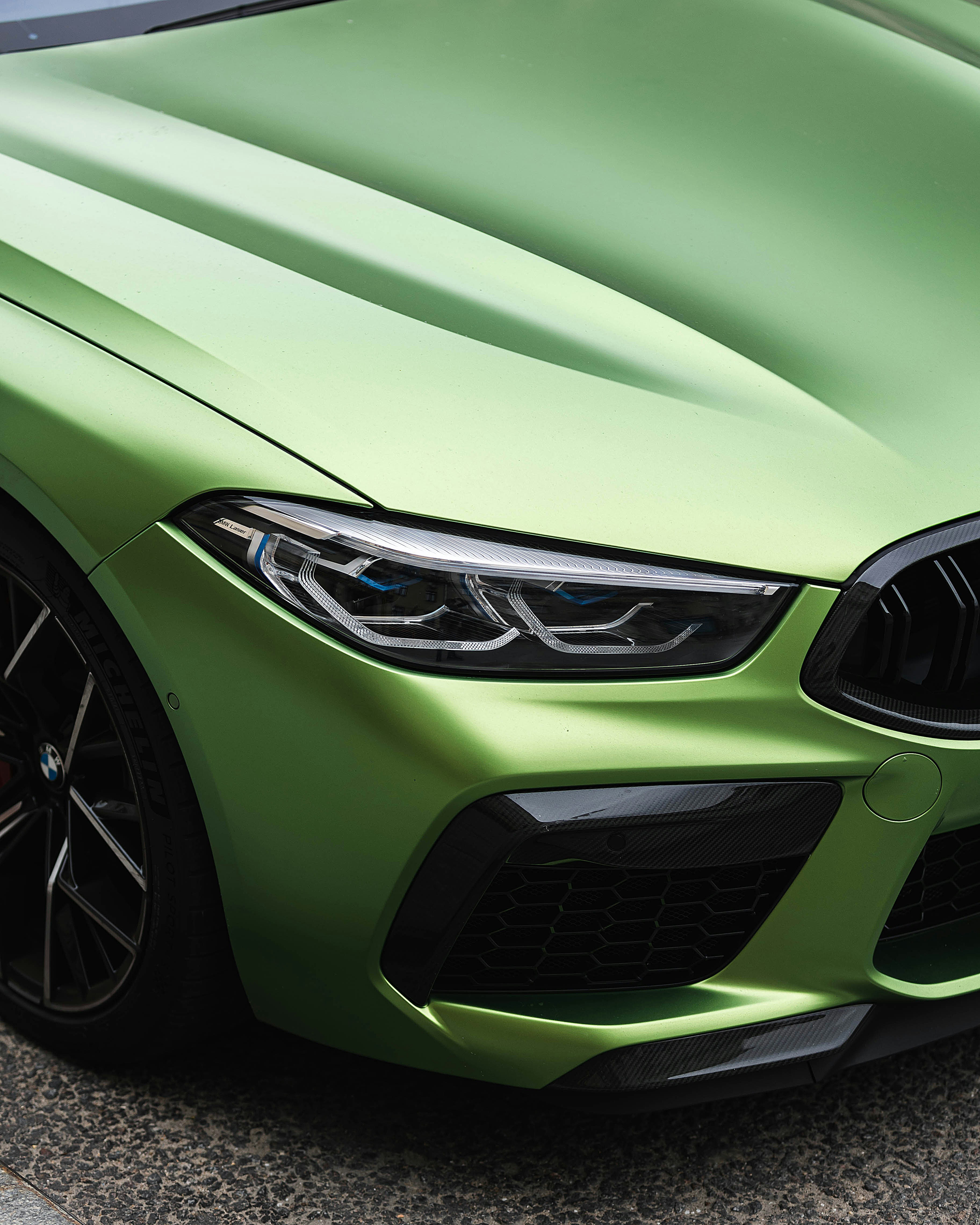 Close-up of a vibrant green BMW car showcasing its sleek design and striking headlights.