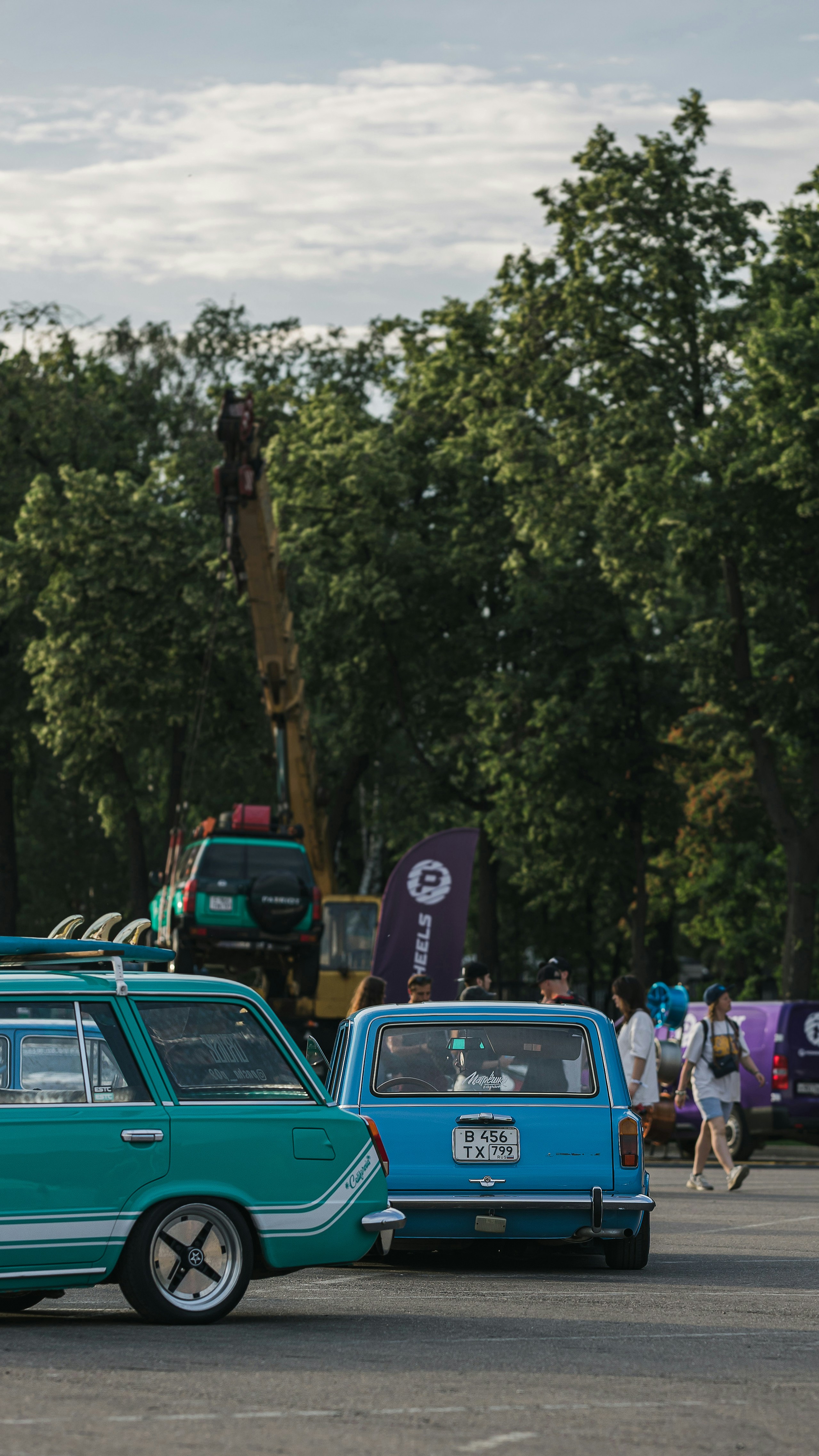 Two vintage station wagons parked outdoors with trees behind.