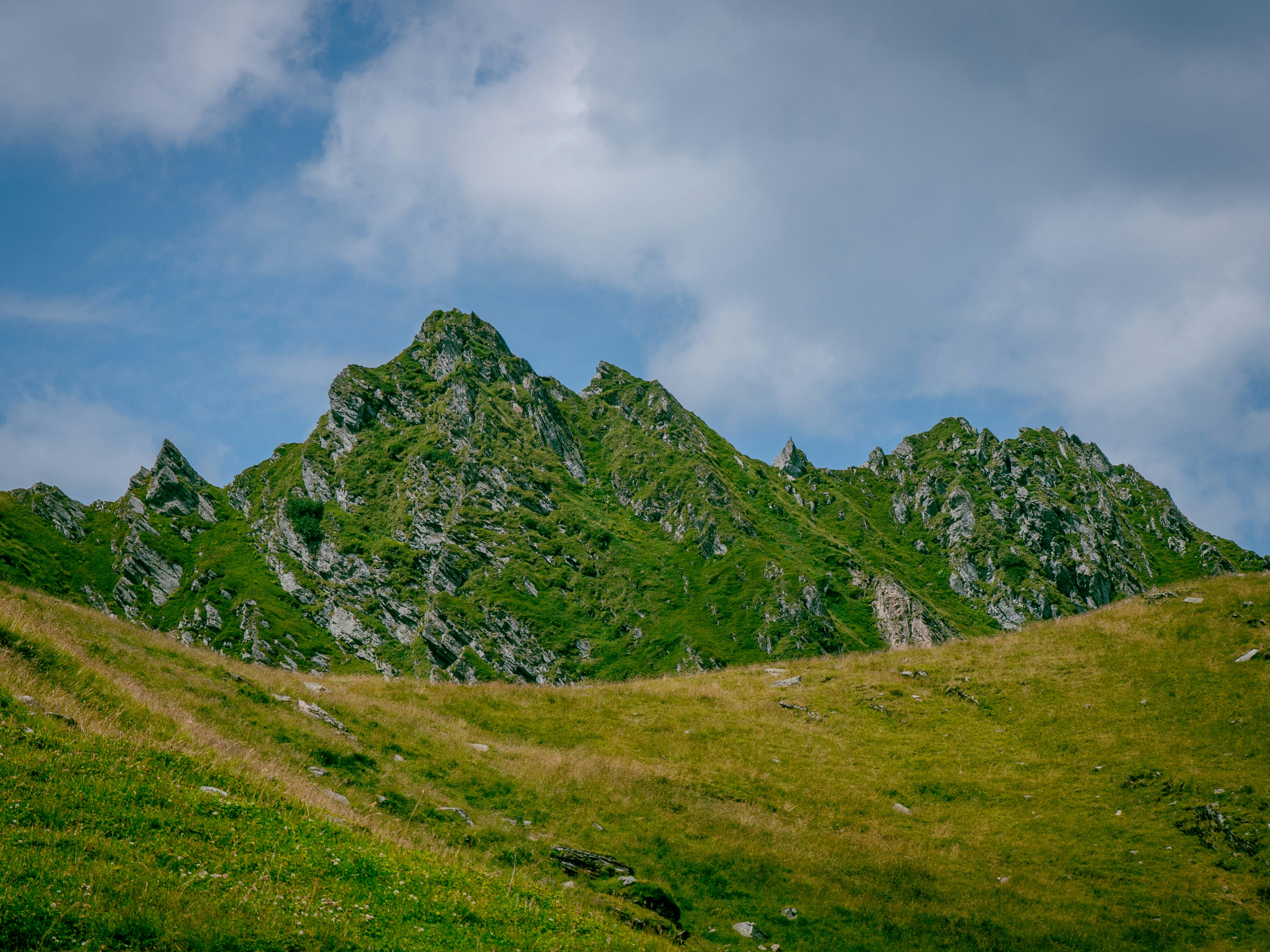Lush green mountains under a cloudy blue sky