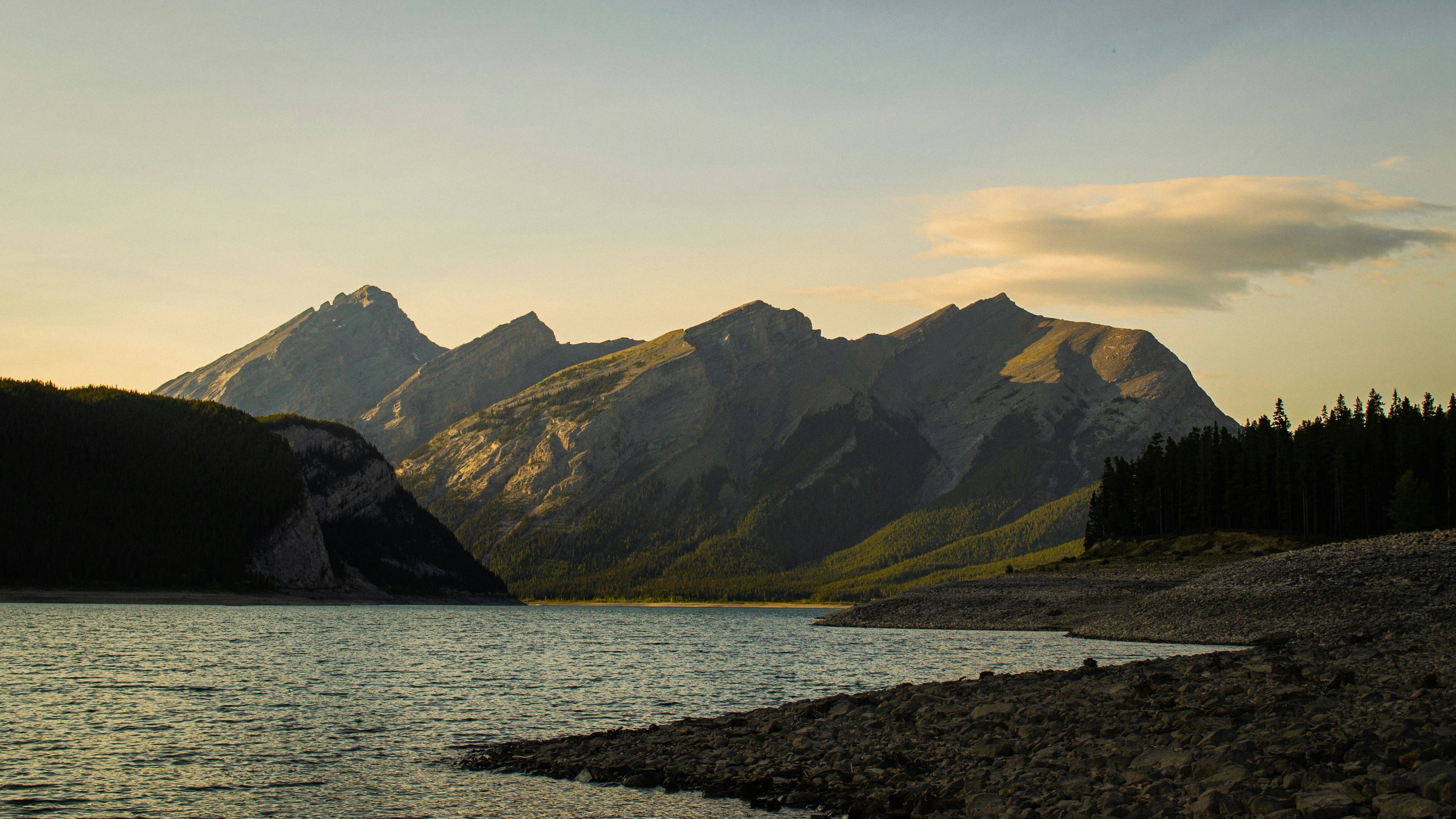 A stunning mountain landscape bathed in golden sunset light, showcasing rugged peaks and textured terrain.
