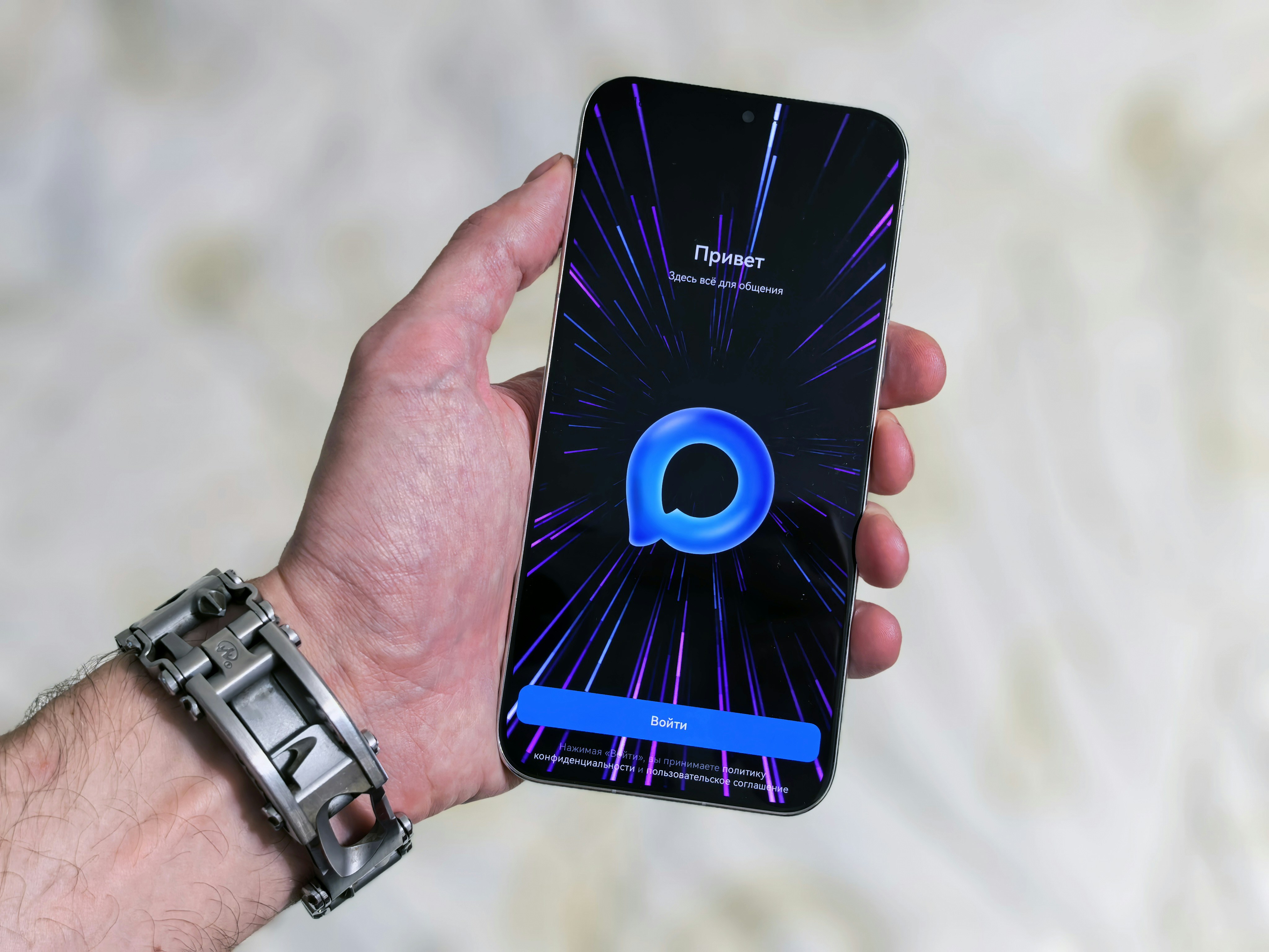 Hand holding smartphone with glowing purple abstract background.