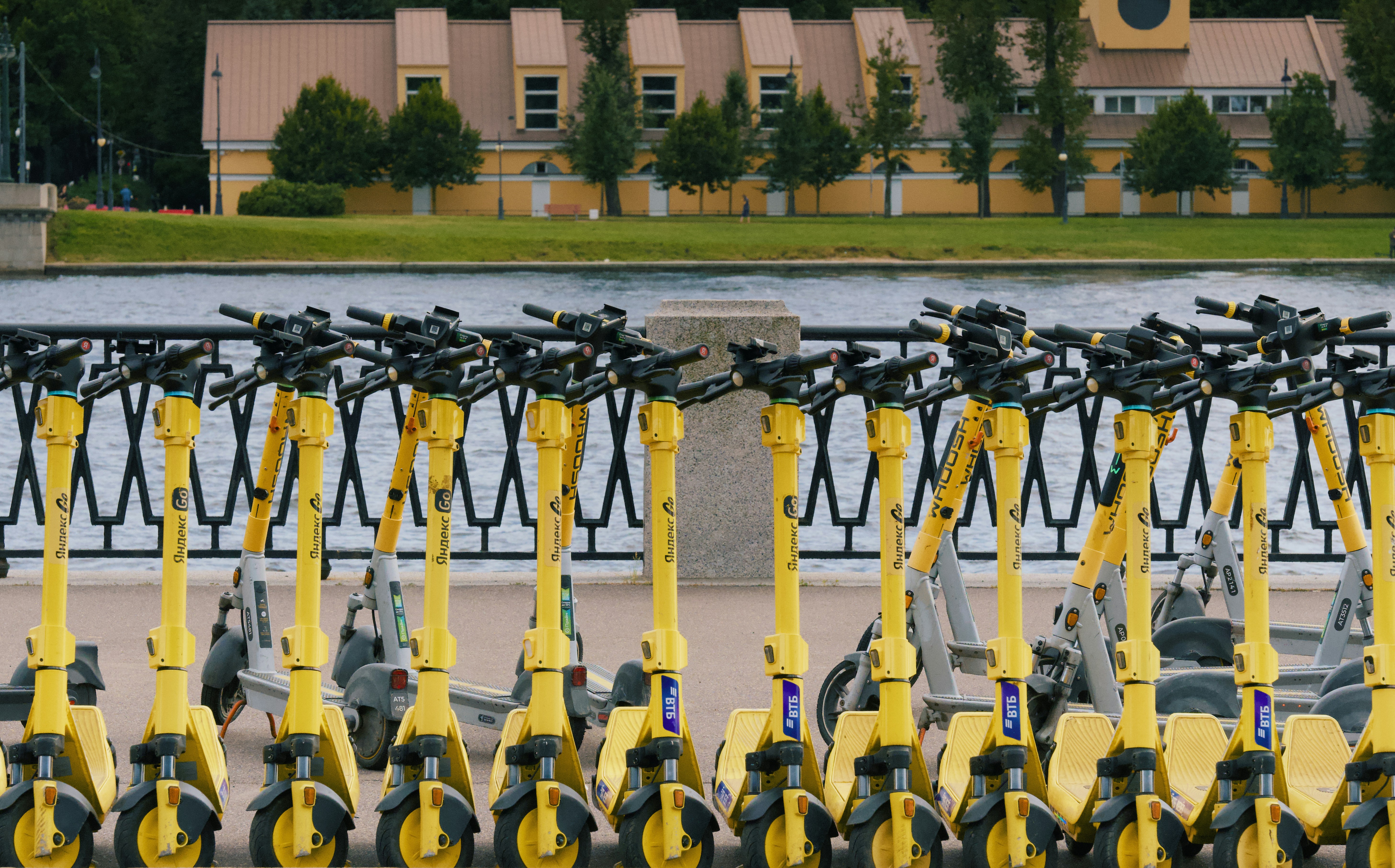 Row of yellow electric scooters parked along waterfront