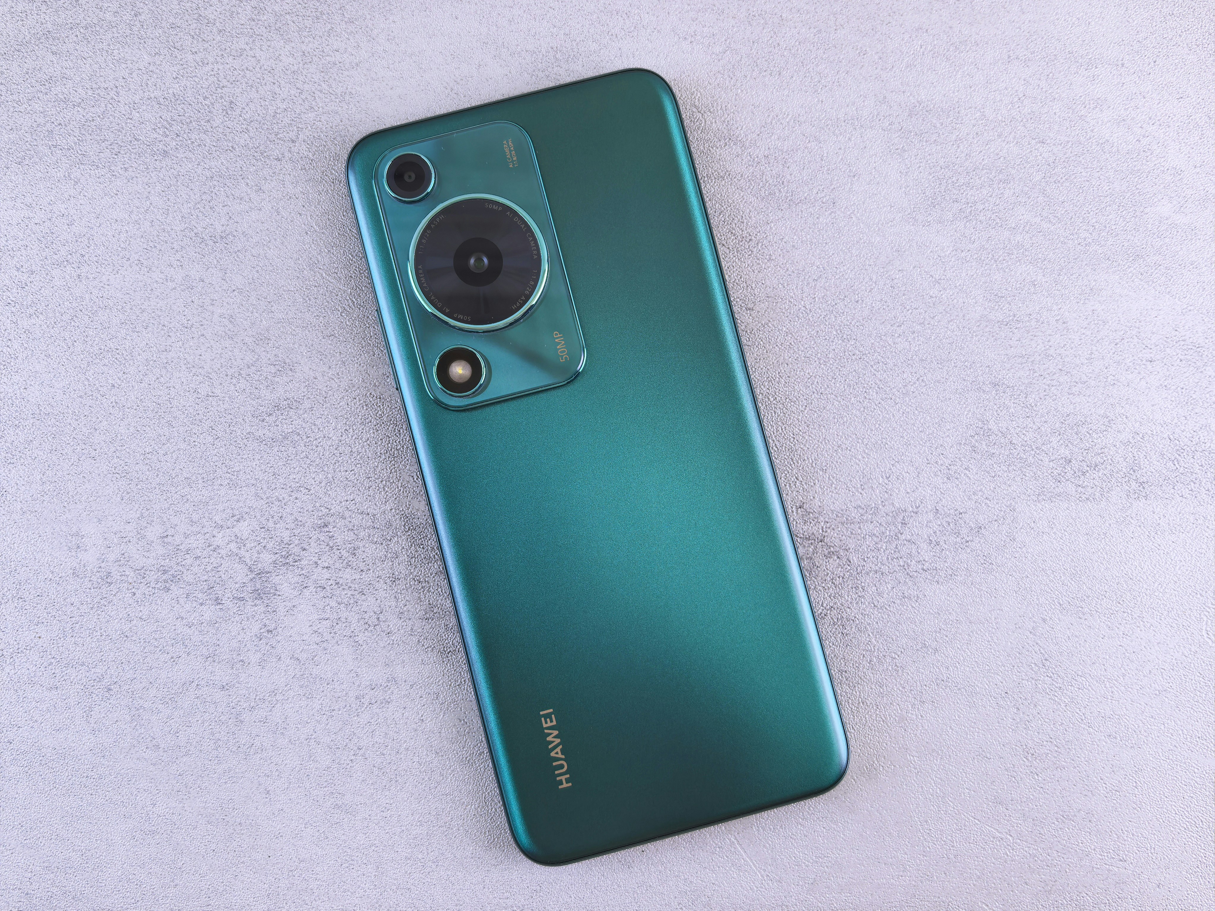 Sleek teal smartphone showcasing its camera and design features on a textured surface.