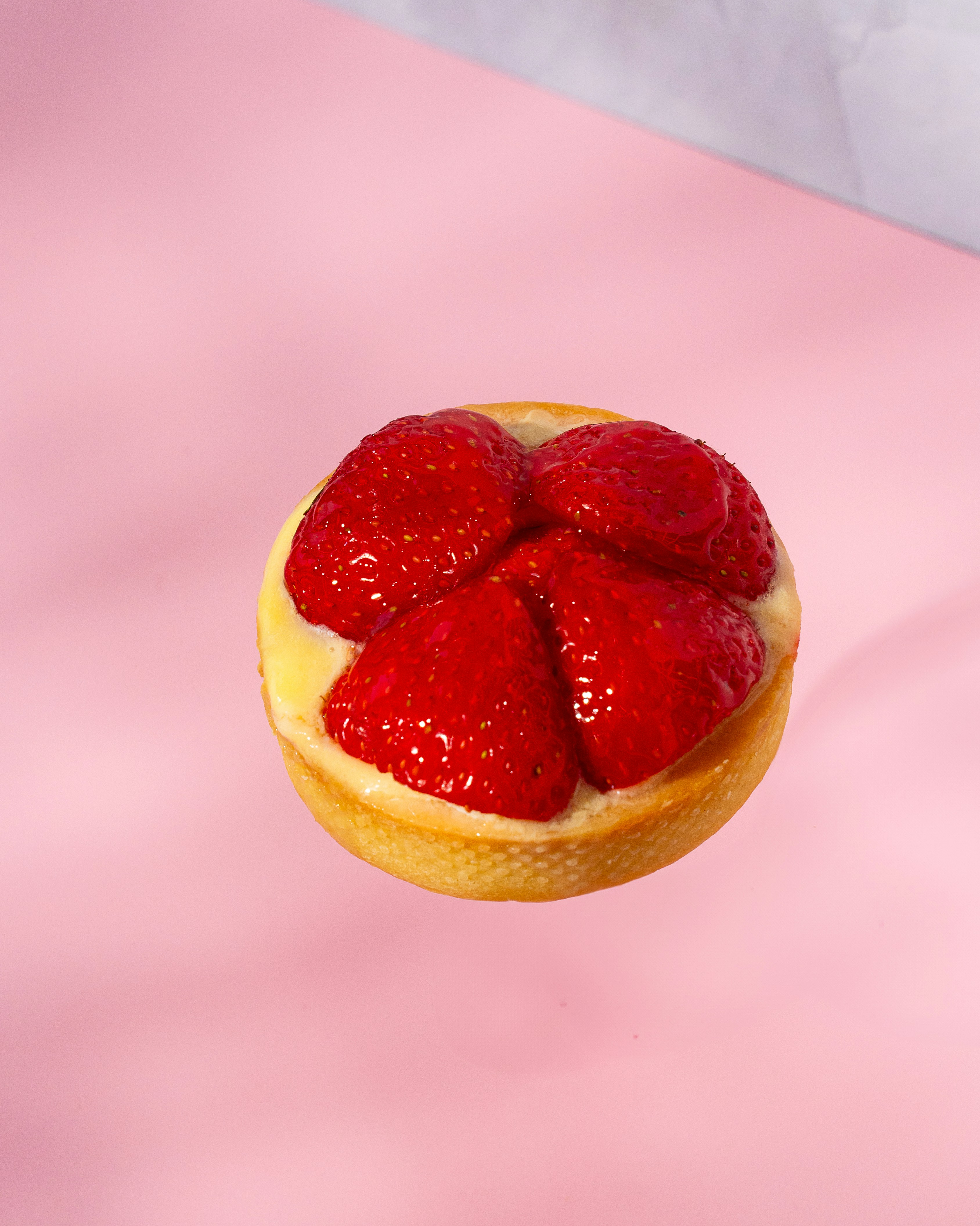 Strawberry tart with cream on pink background