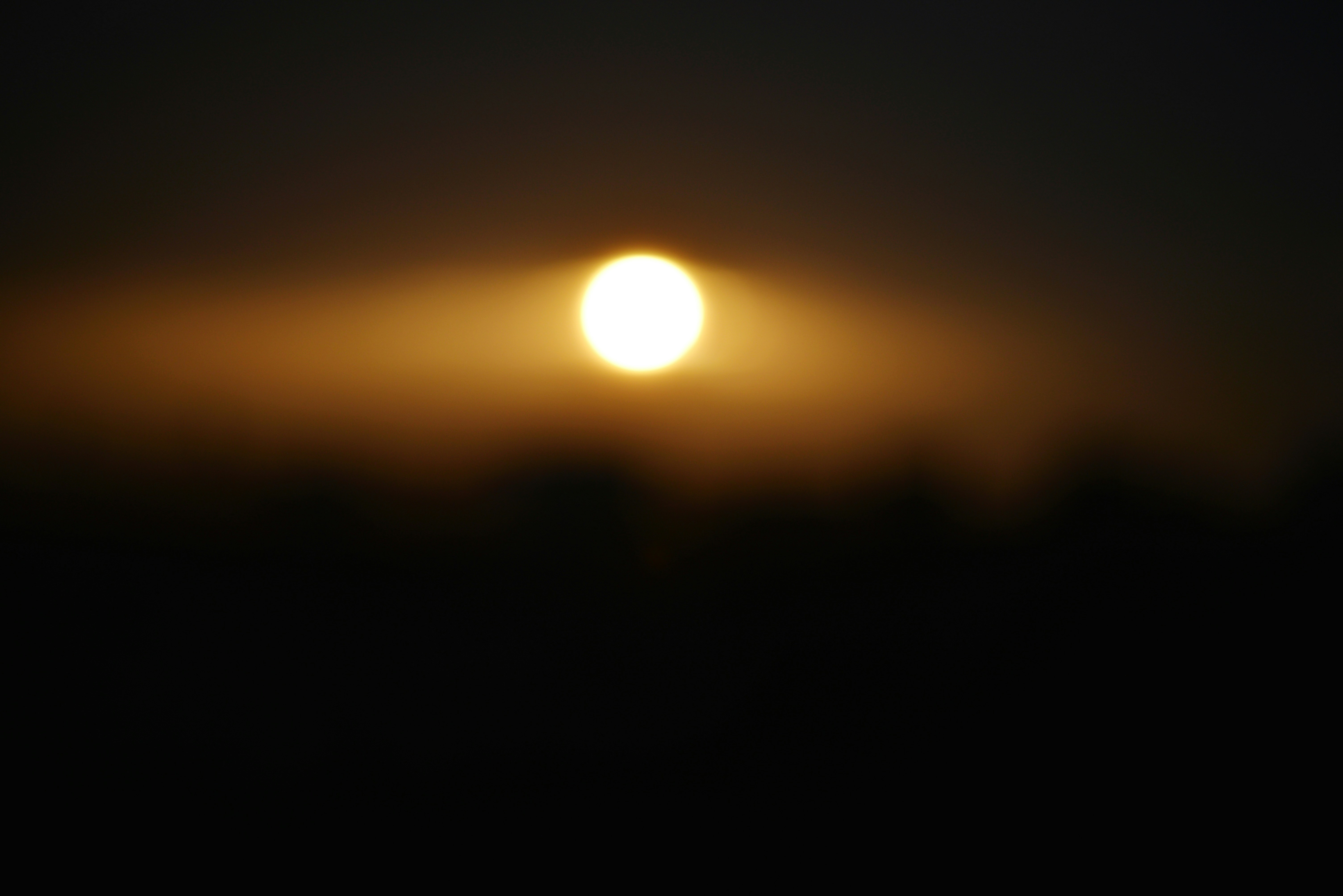 Bright sun setting over a dark, blurry landscape