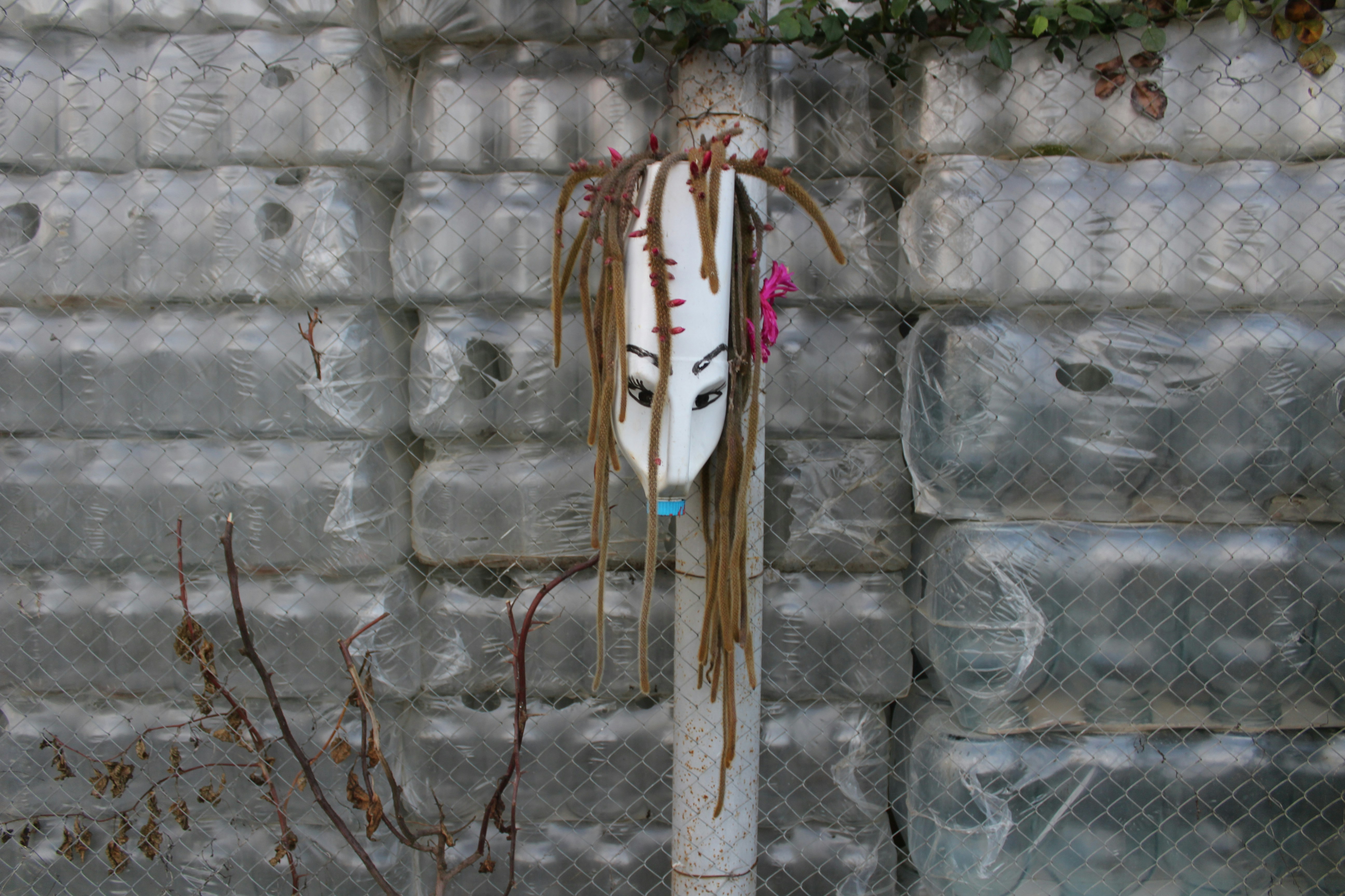 Amazing artwork | A mask made from plastic bottles hangs on a pole.