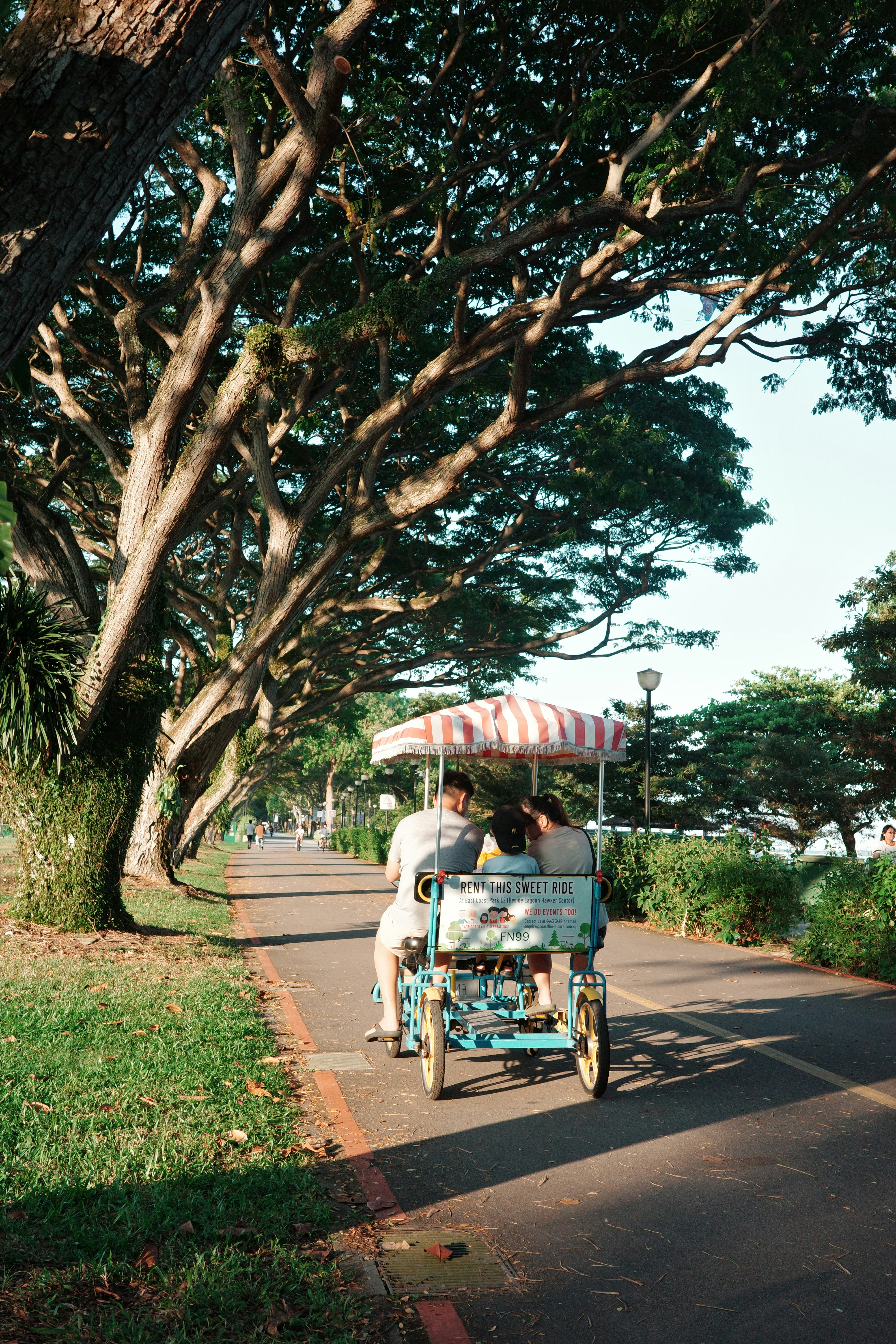 People ride a surrey bike along a paved path.