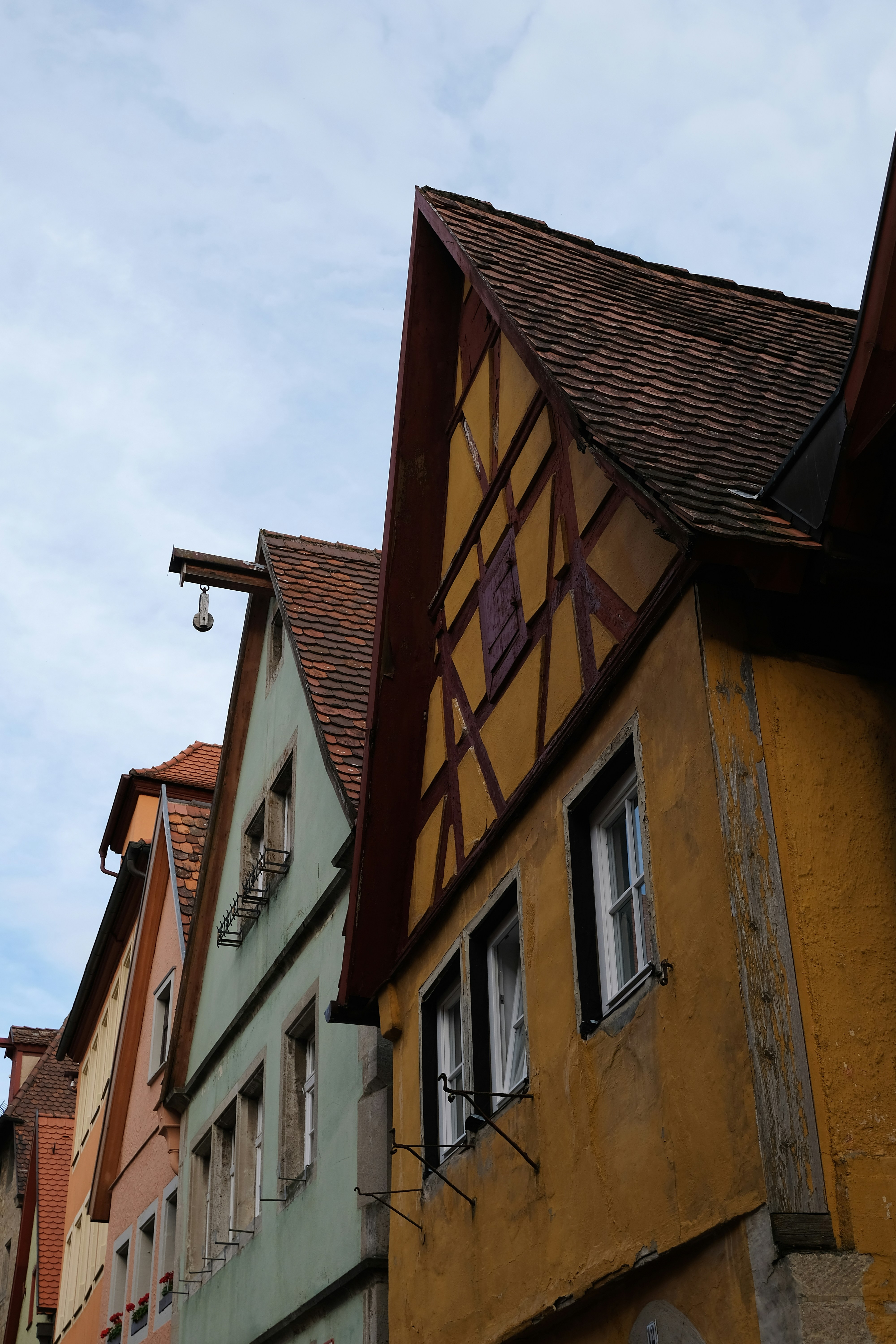 Colorful medieval buildings with intricate rooflines and window details lining a narrow street. A blend of historical charm and architectural diversity.