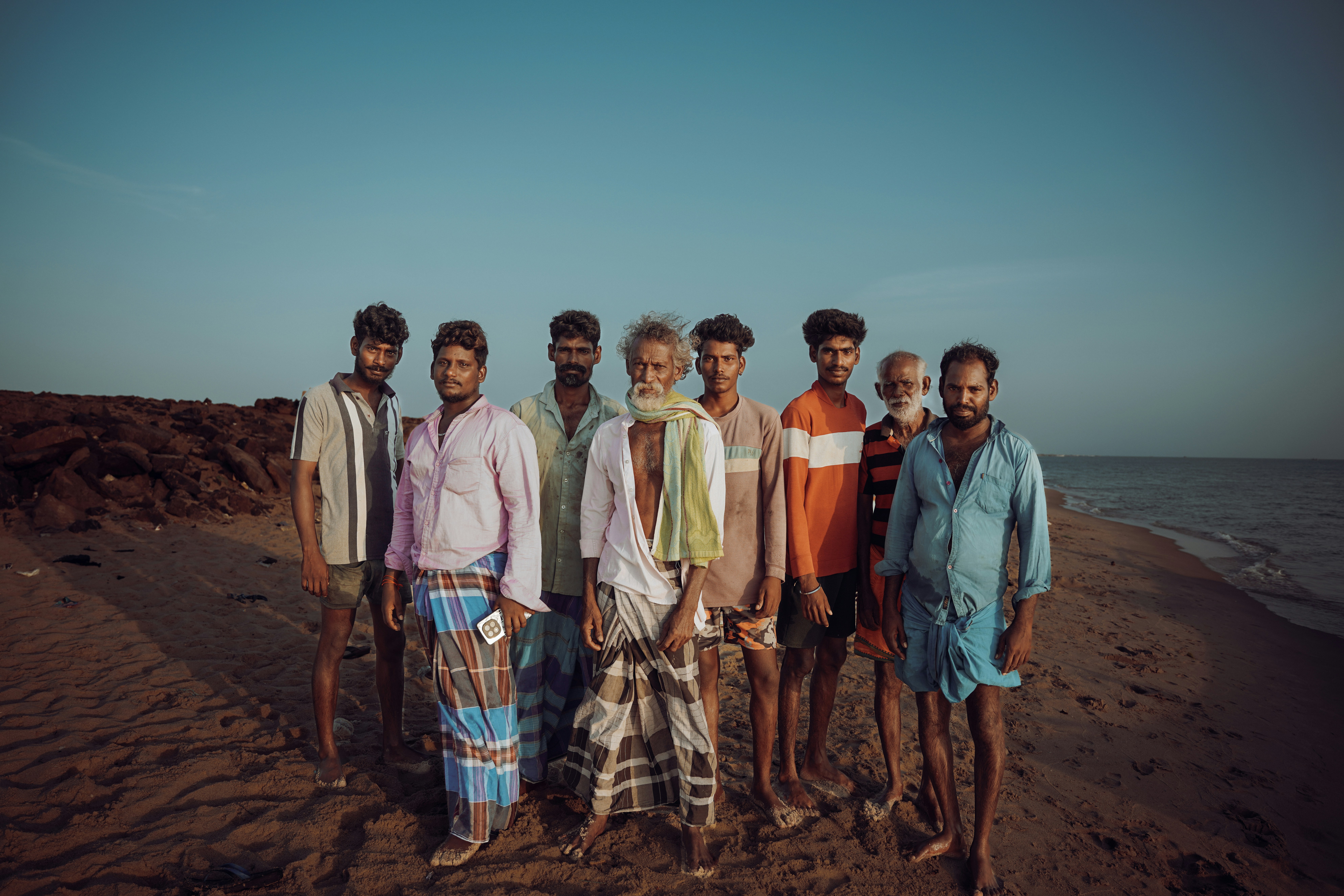 Group of men standing on a beach at sunset