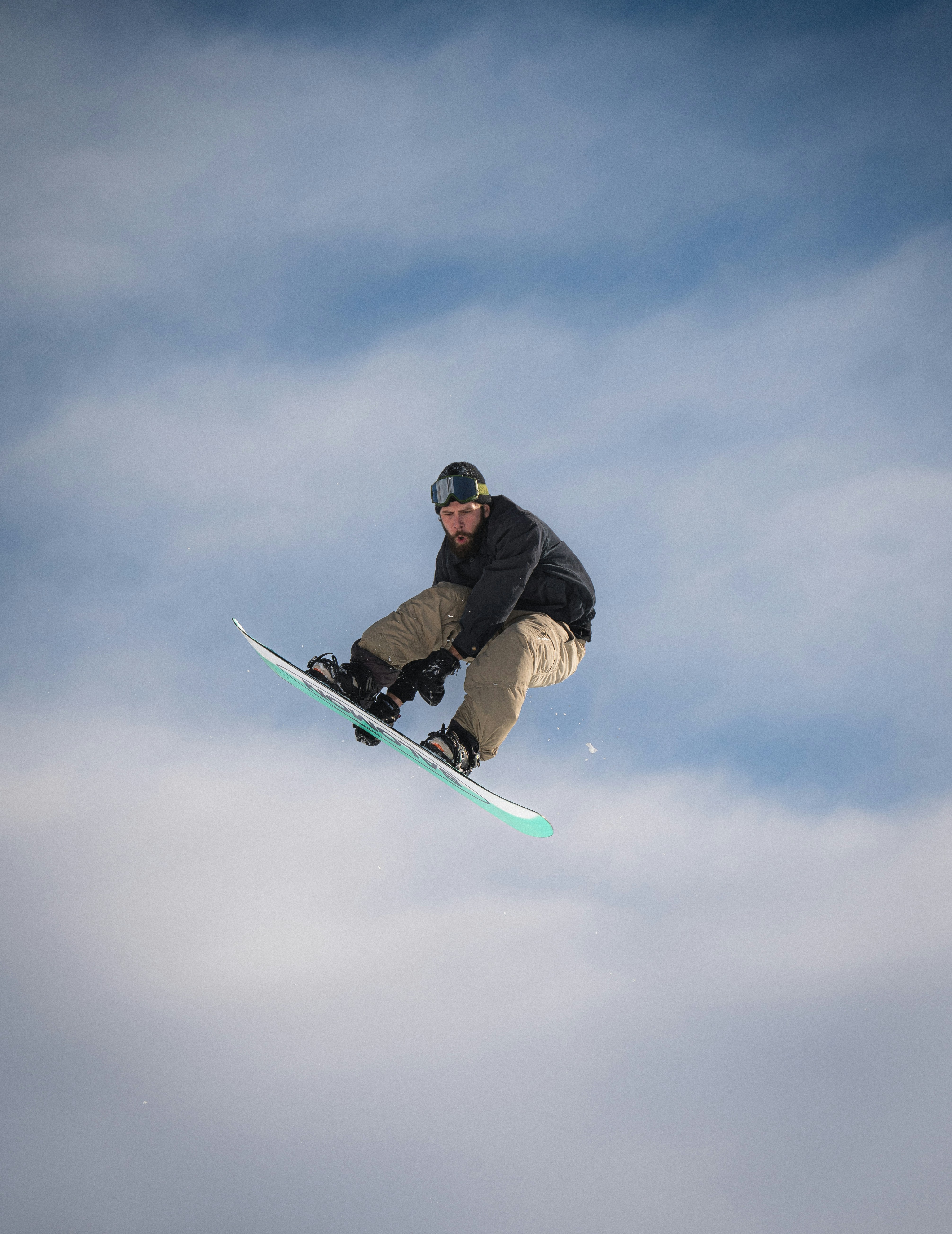 Snowboarder performs a trick against a cloudy sky