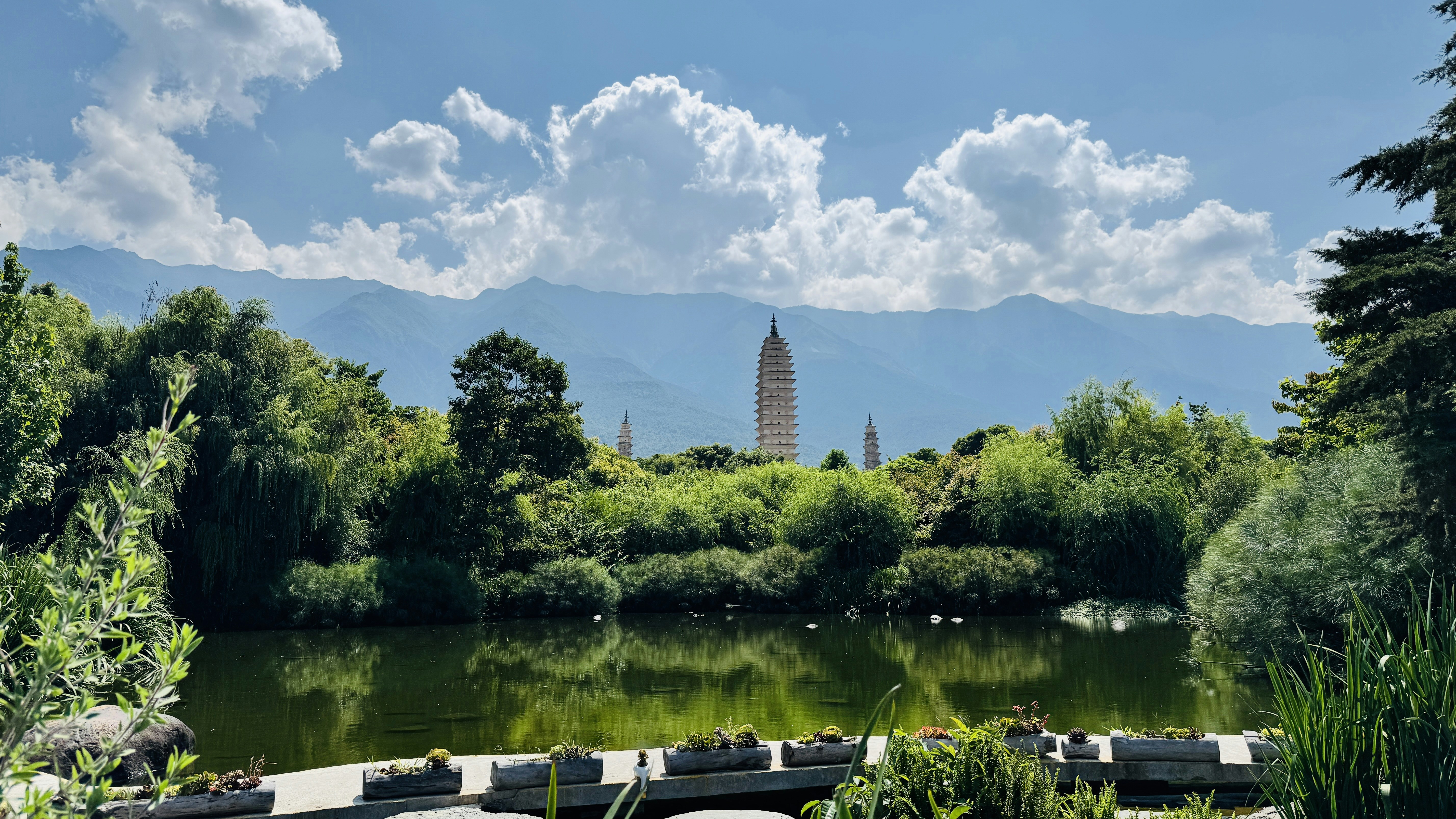 Lush Riverside with Distant Temple Towers under a Bright Sky