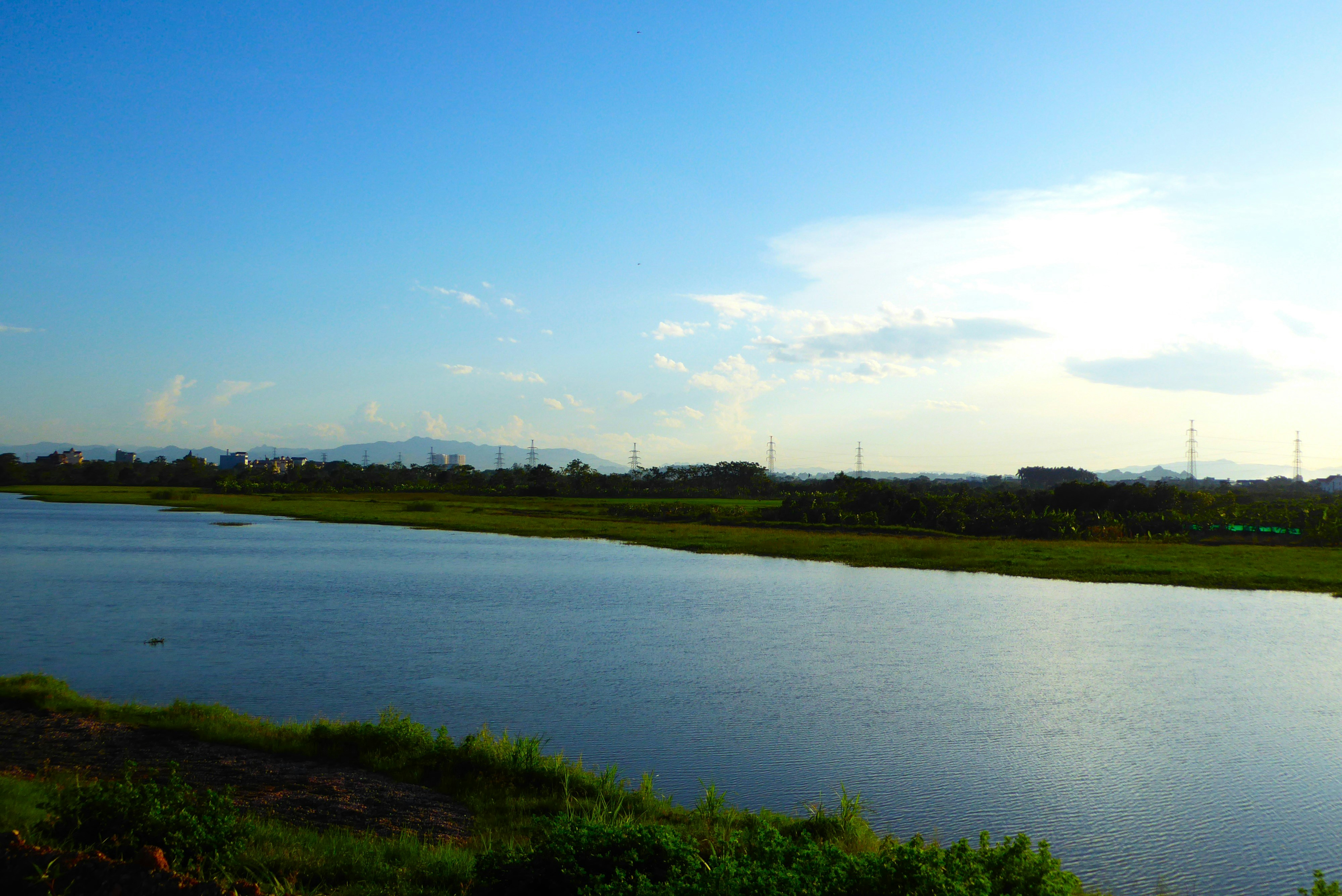 Calm river flowing through green landscape under blue sky