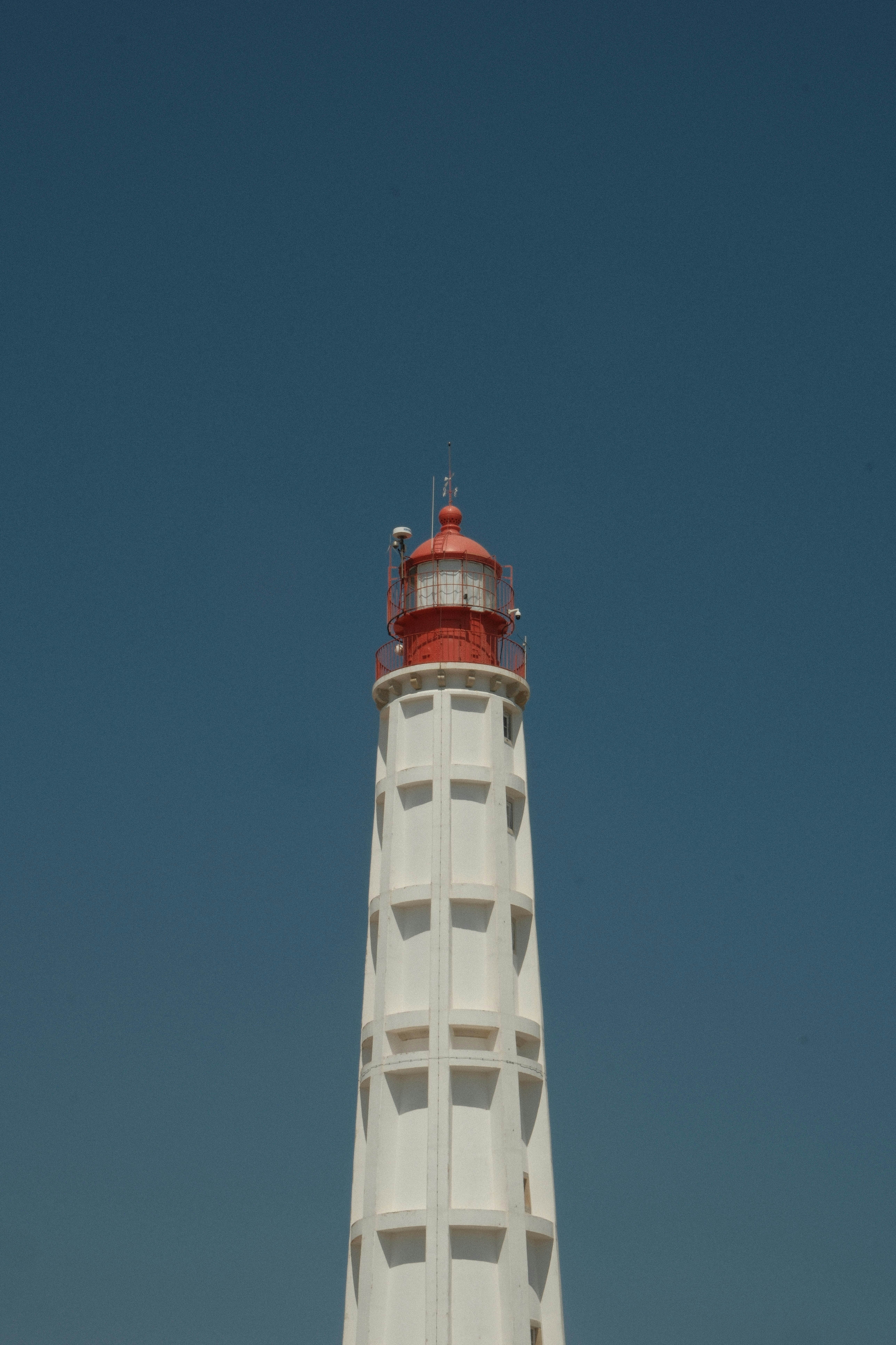 Algarve shot on Fujifilm XT-5. | Tall white lighthouse with red top against blue sky