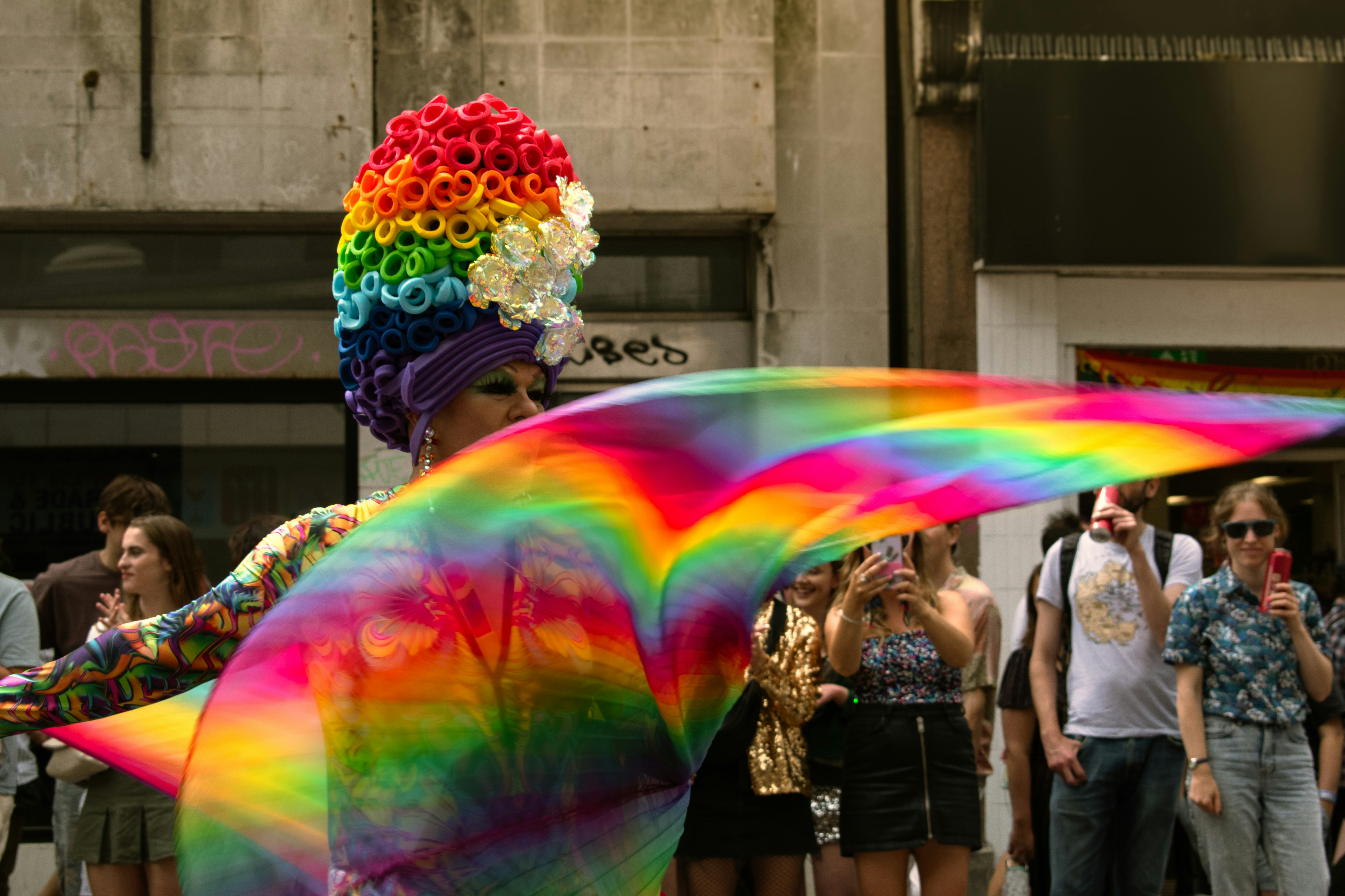 Person in rainbow wig holds large rainbow flag at parade. photo – Free ...