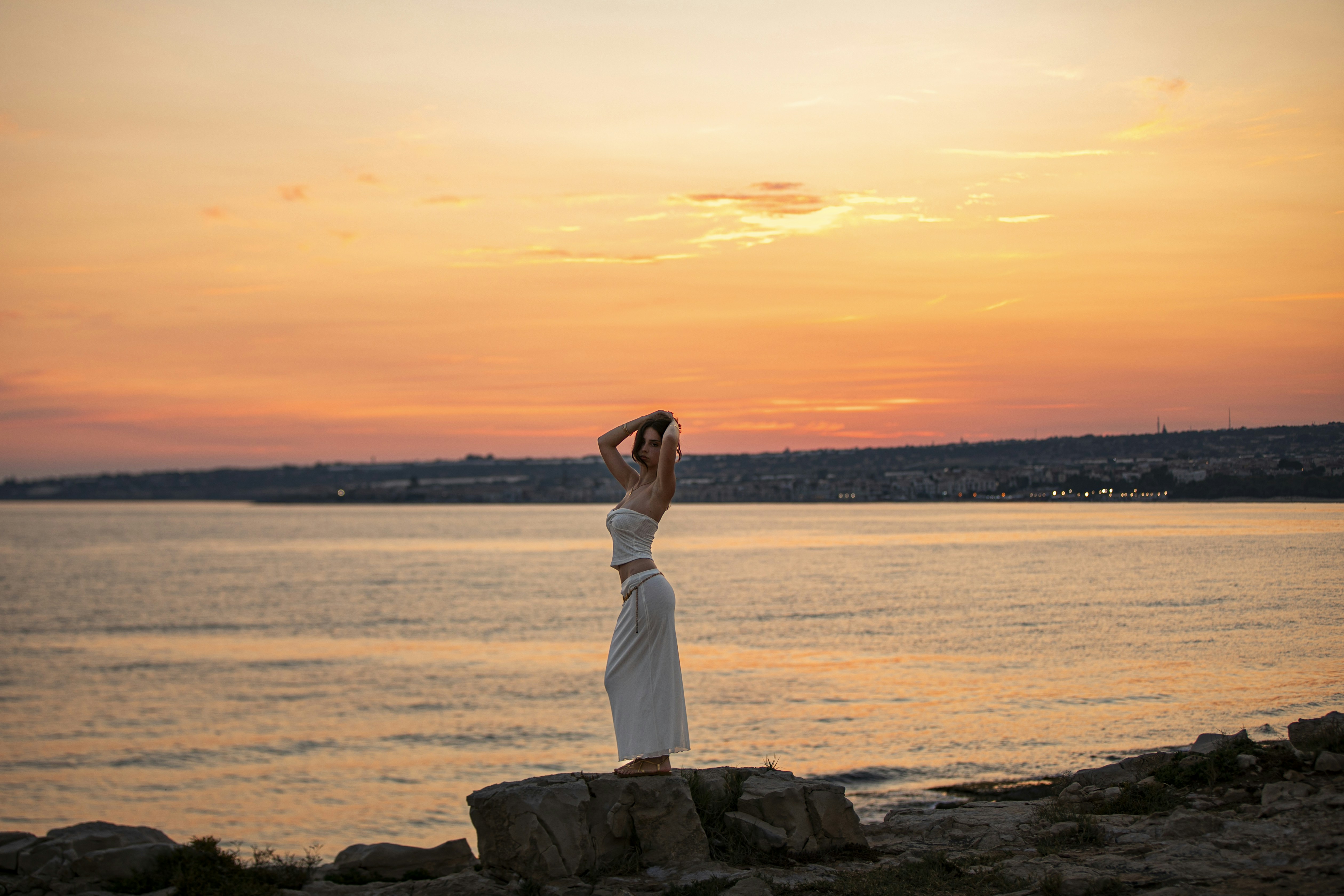 Woman in white dress by the ocean at sunset