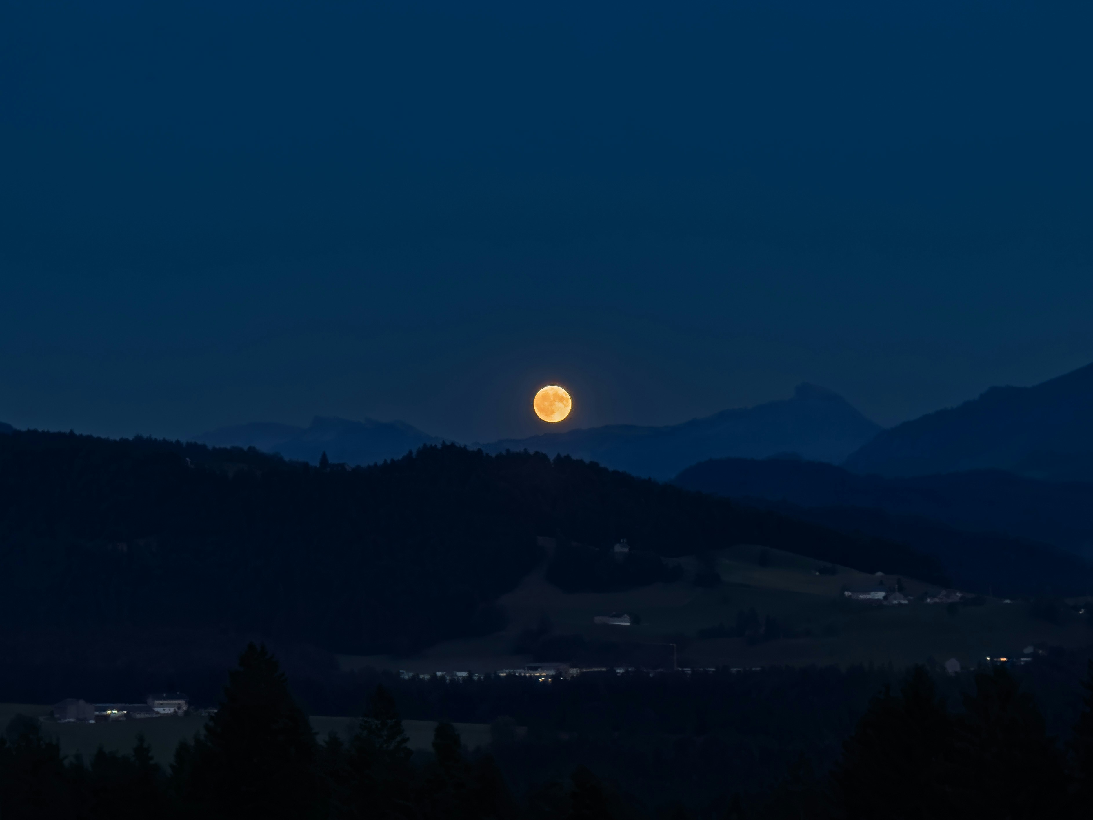 Full moon rising over dark mountain landscape